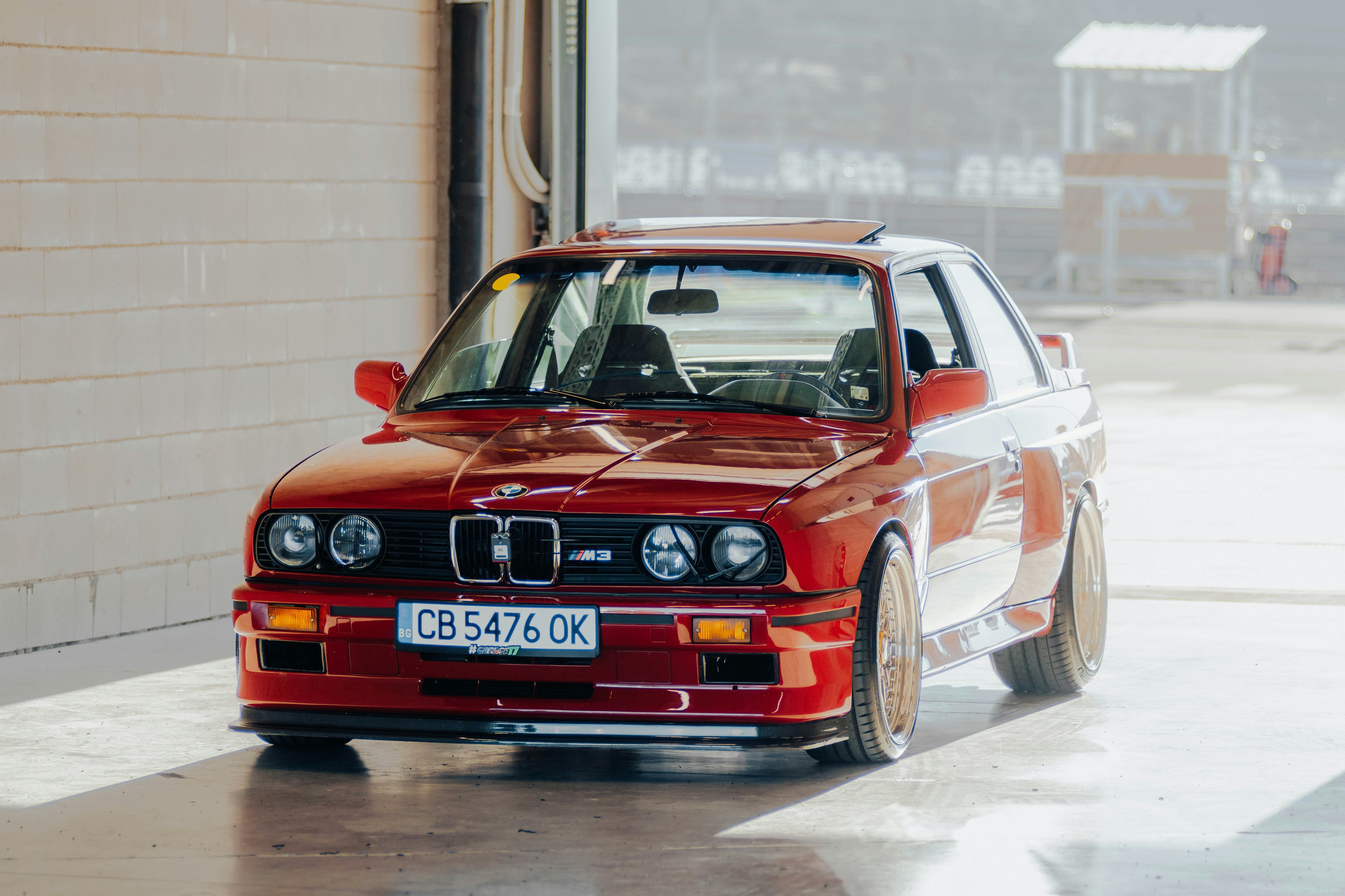 Red BMW E36 M3 in a sunlit workshop, ready for a race-day thaw
