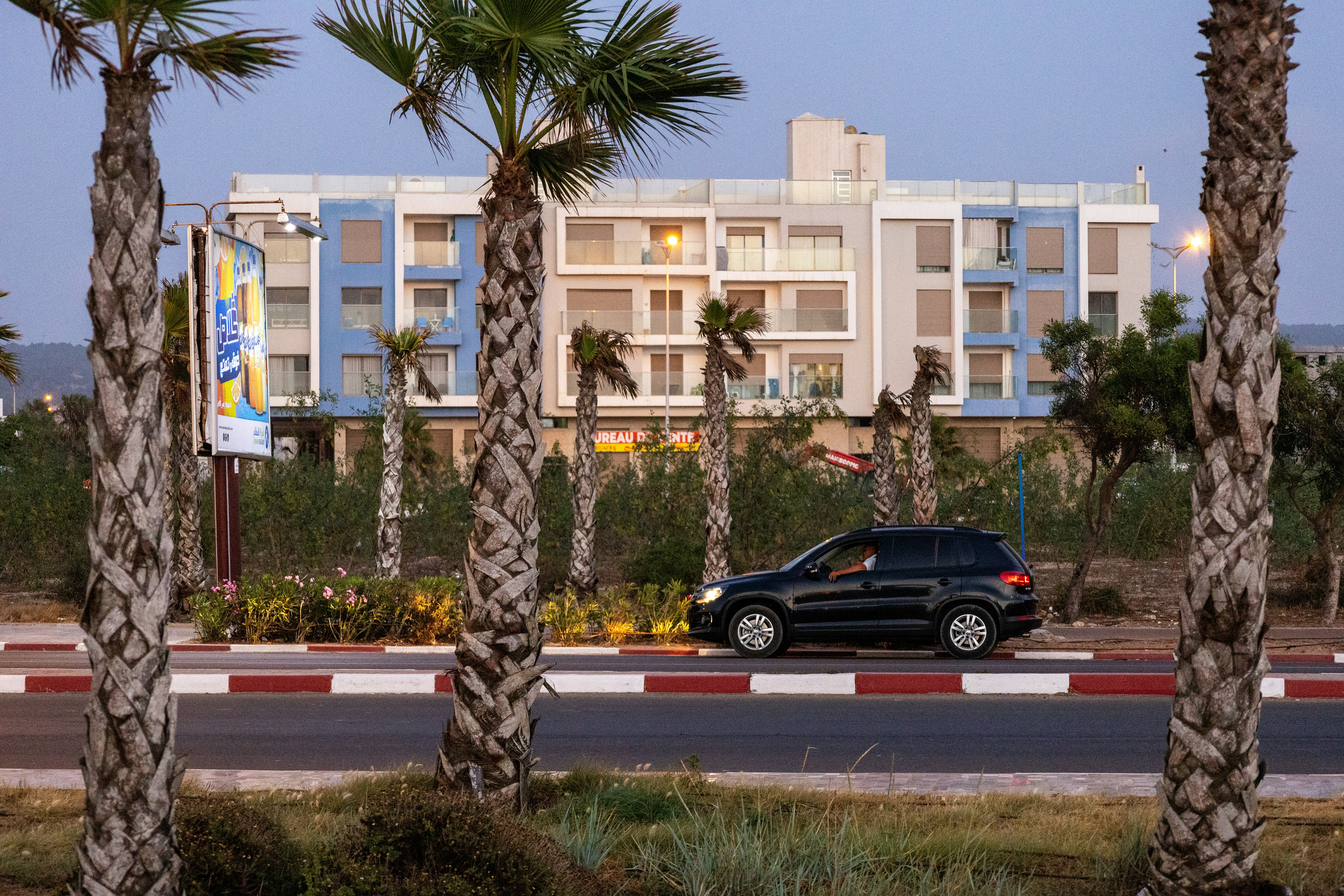 Midtown Drive: A Black SUV Rides Past Palm-Lined Apartments