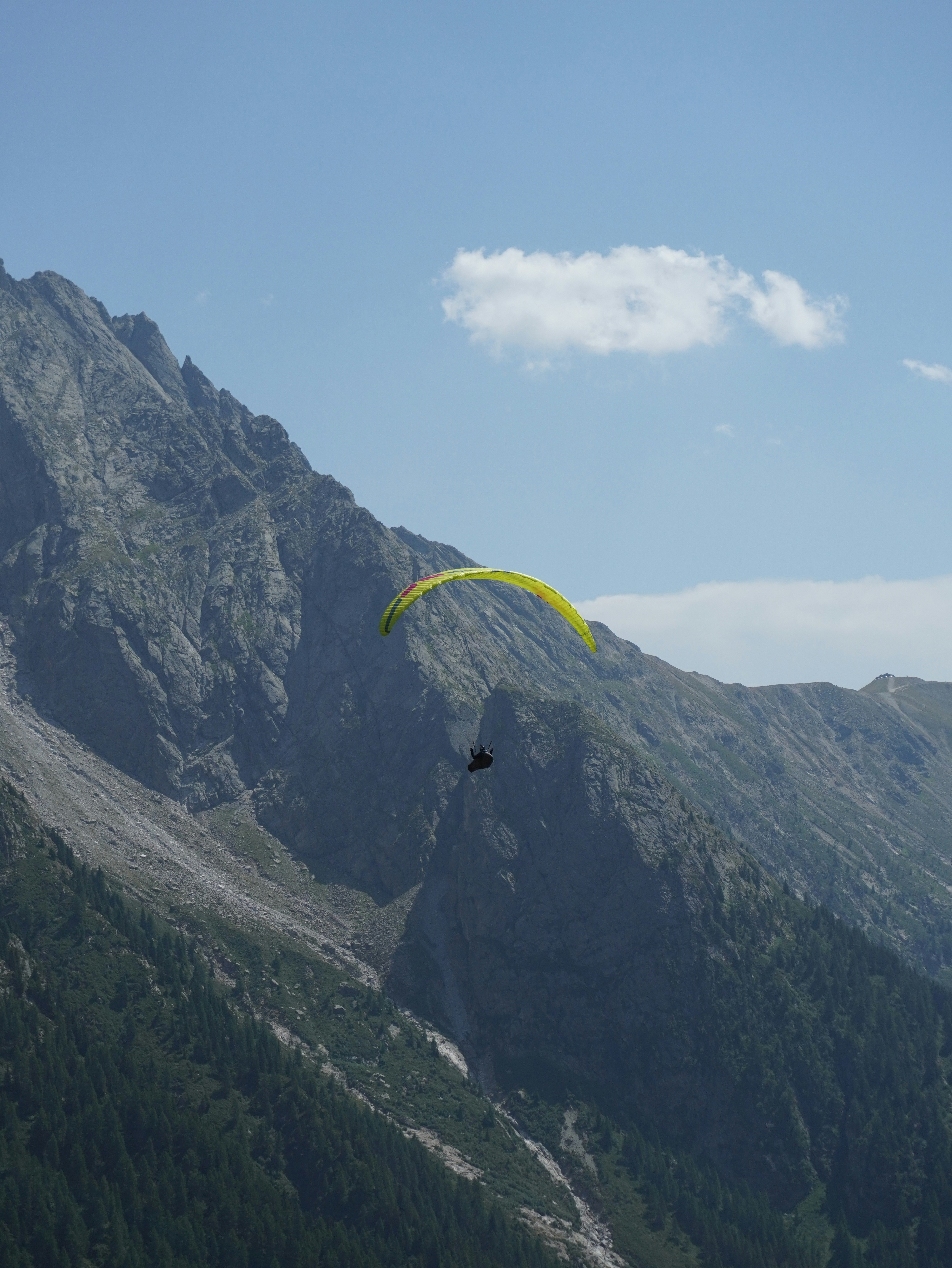 Soaring Silhouette: A lone paraglider against jagged Alpine peaks