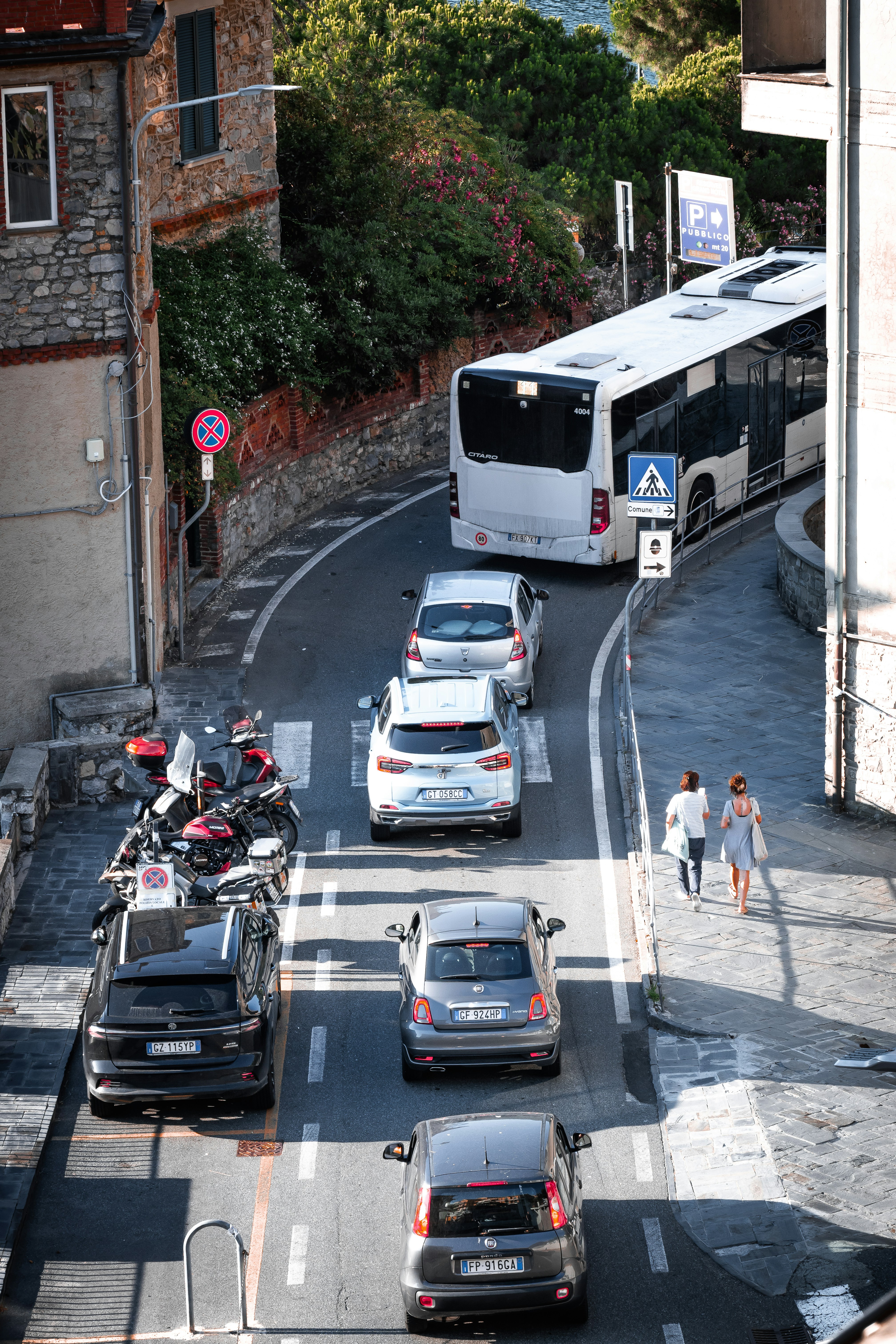 Narrow Road, Busy Corridor: A Bus and Cars Thread Through a Stony Hill Town