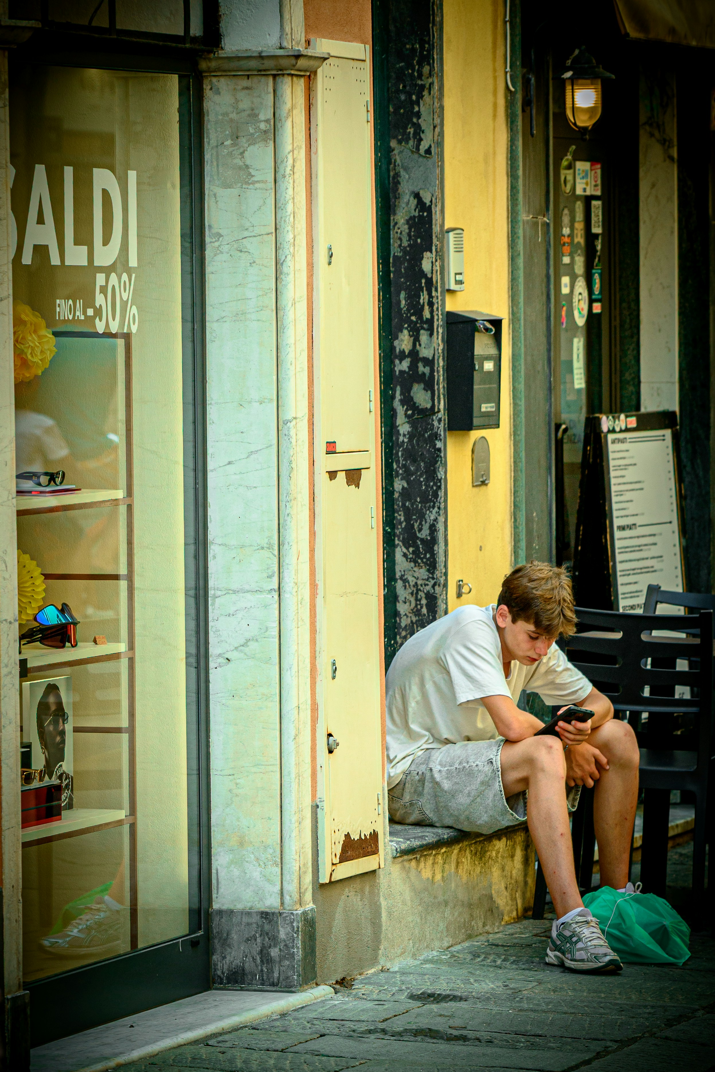 Teenager on a quiet street corner absorbed in his phone
