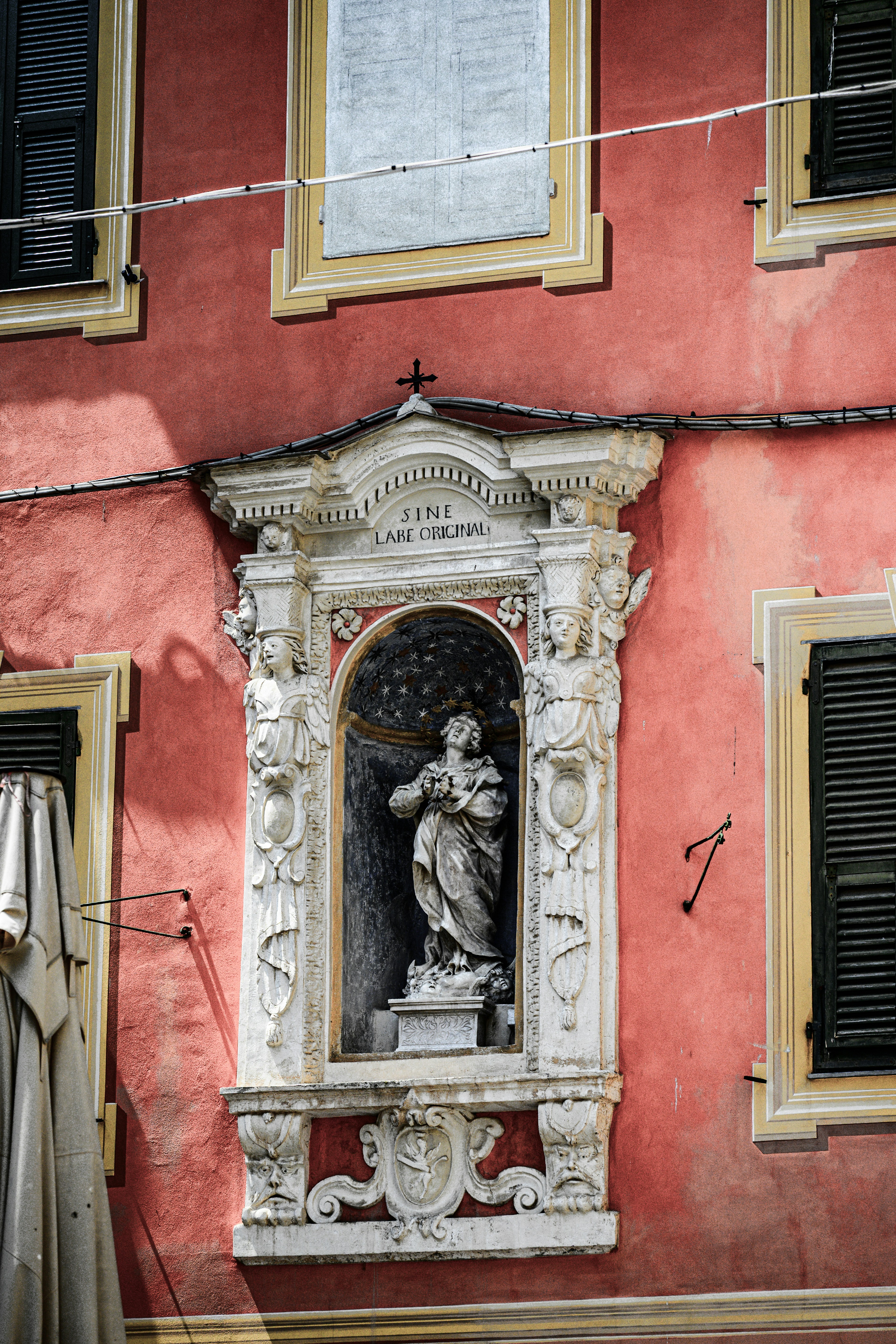Red-walled shrine: carved statue set in a lime-painted niche on a sunlit building