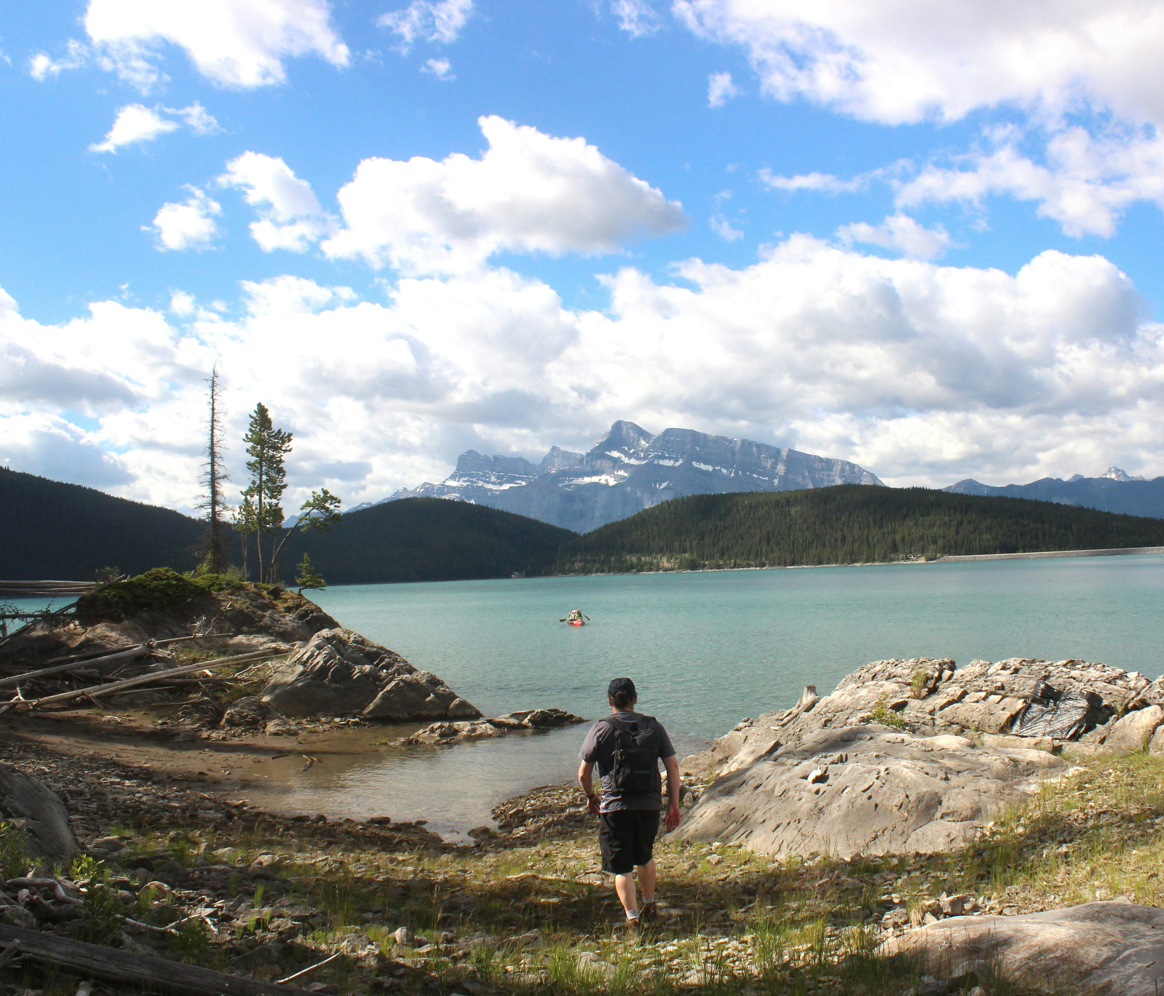 Hiker Approaches Quiet Lake Under Expansive Sky
