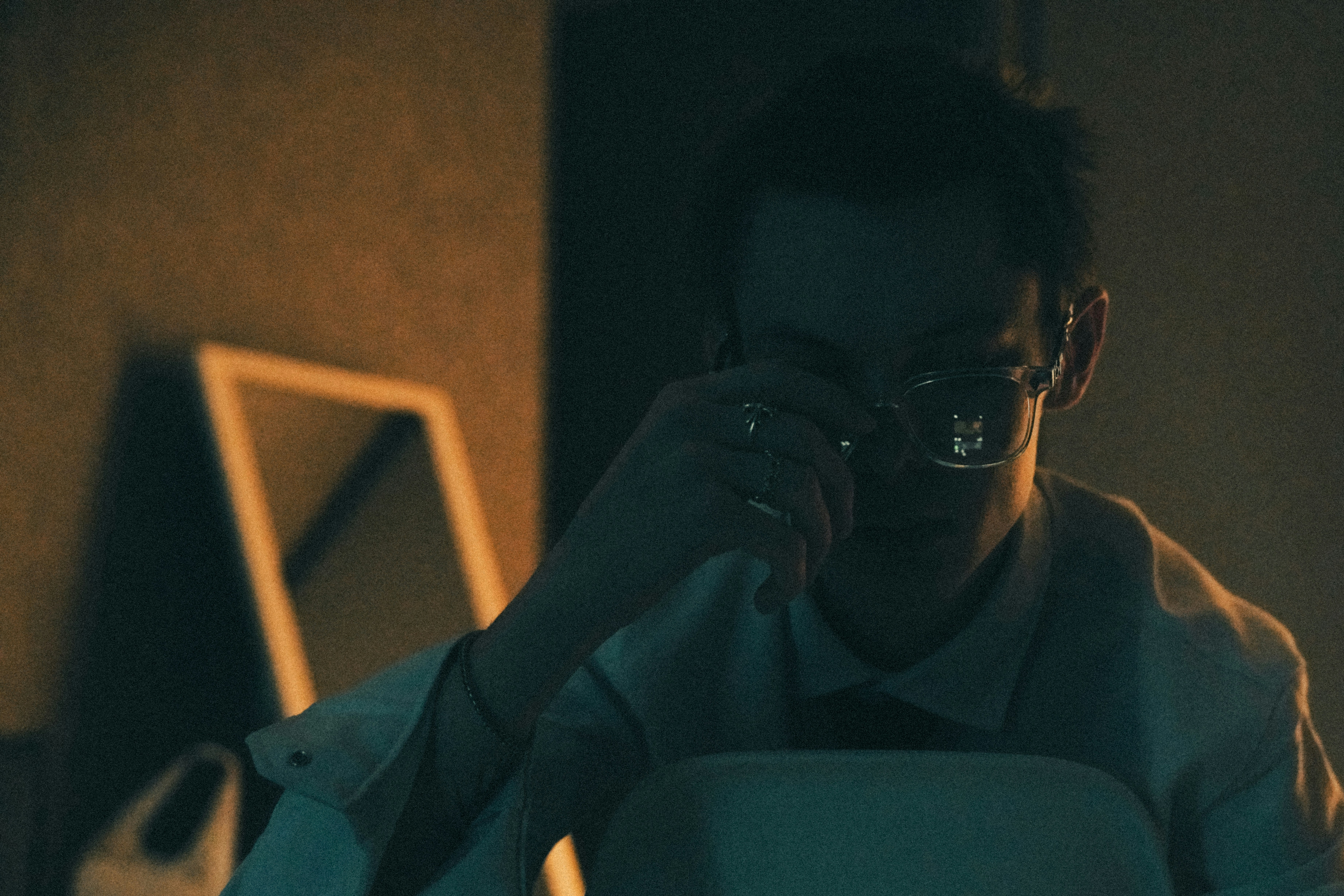 Backlit Quiet Study: A man with glasses in low light adjusting a bowl