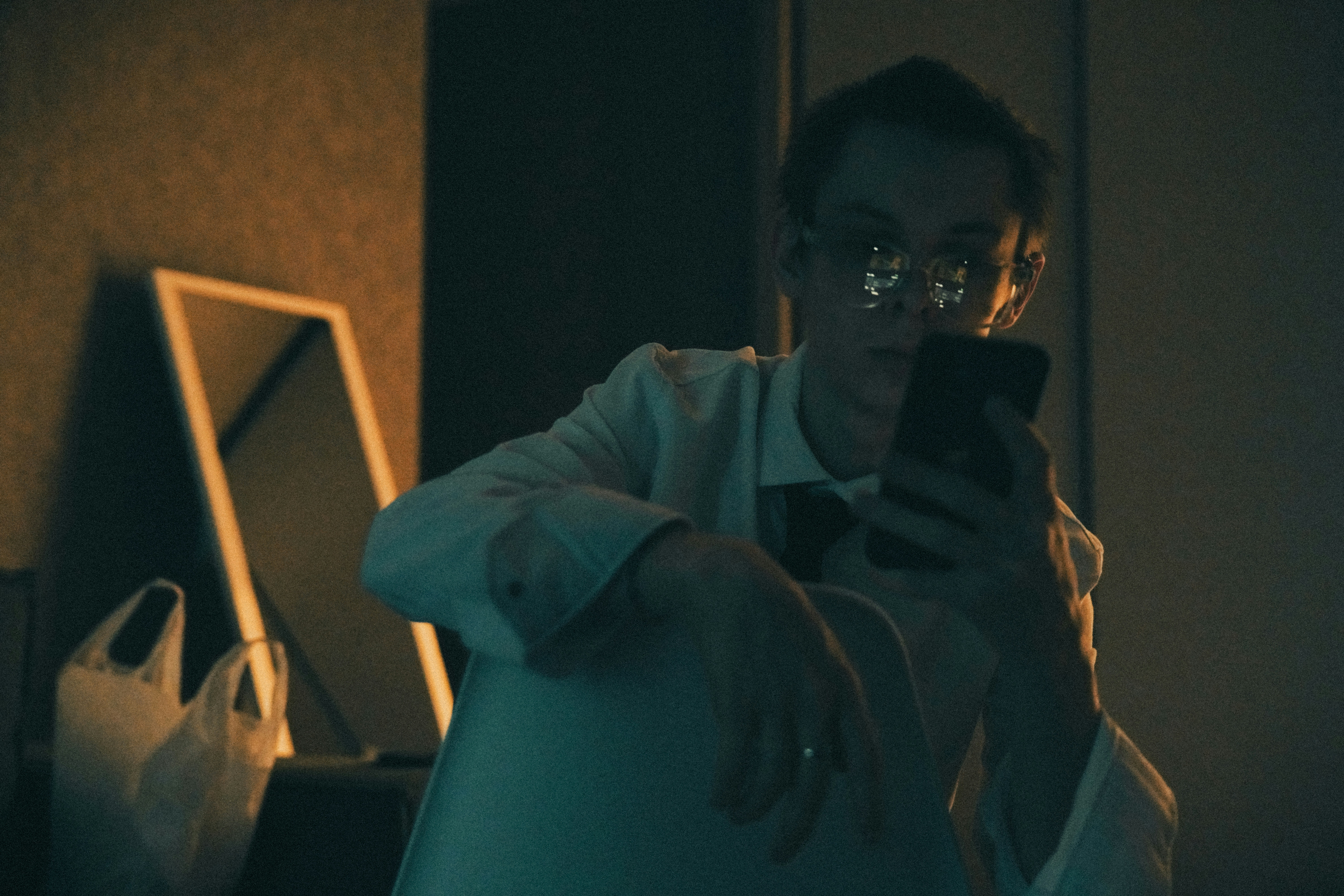 Low-Light Self-Portrait in a Dim Room with Sunglasses and Phone