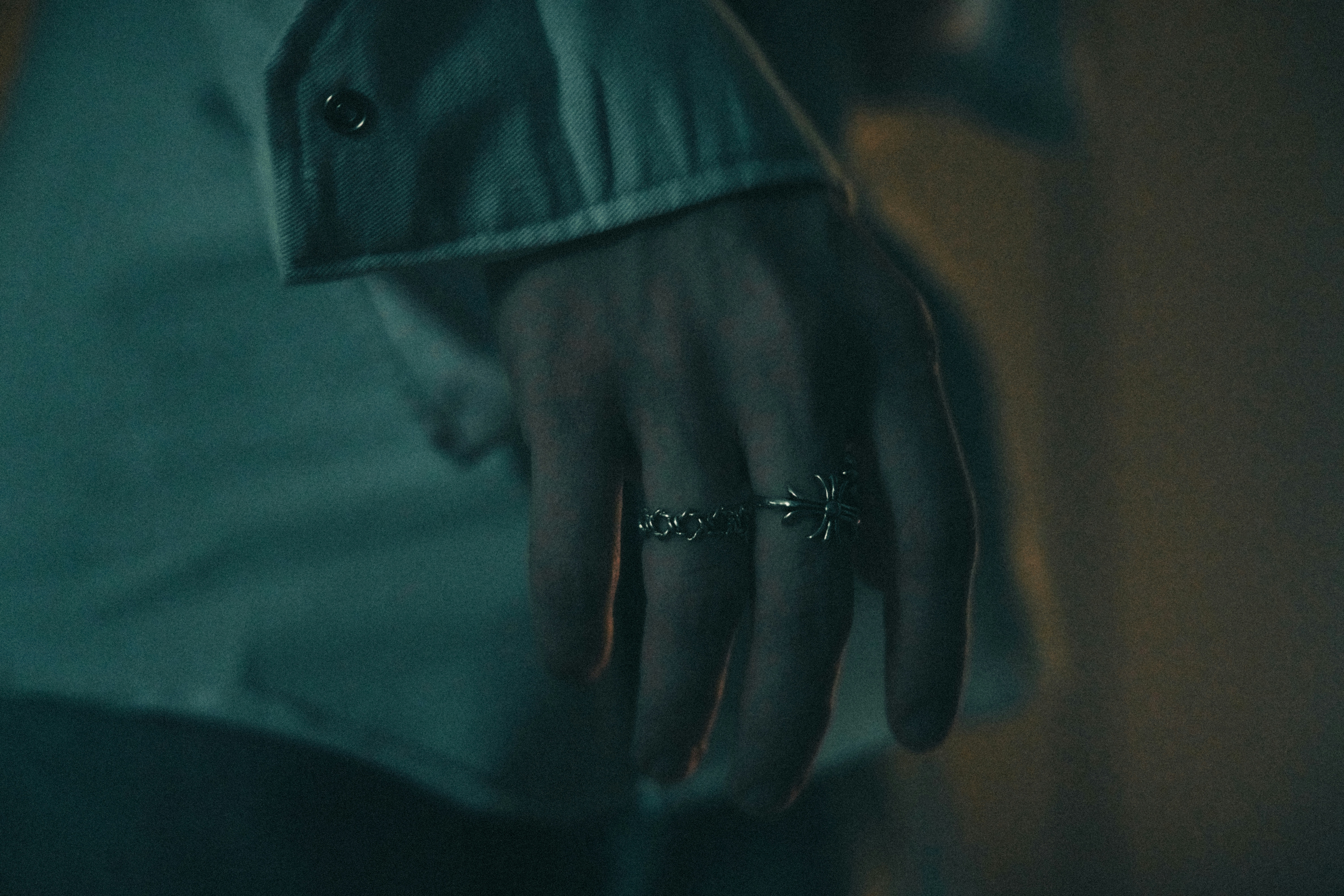 A Quiet Gloom: Diamond Ring Between Fingers in Dim Light