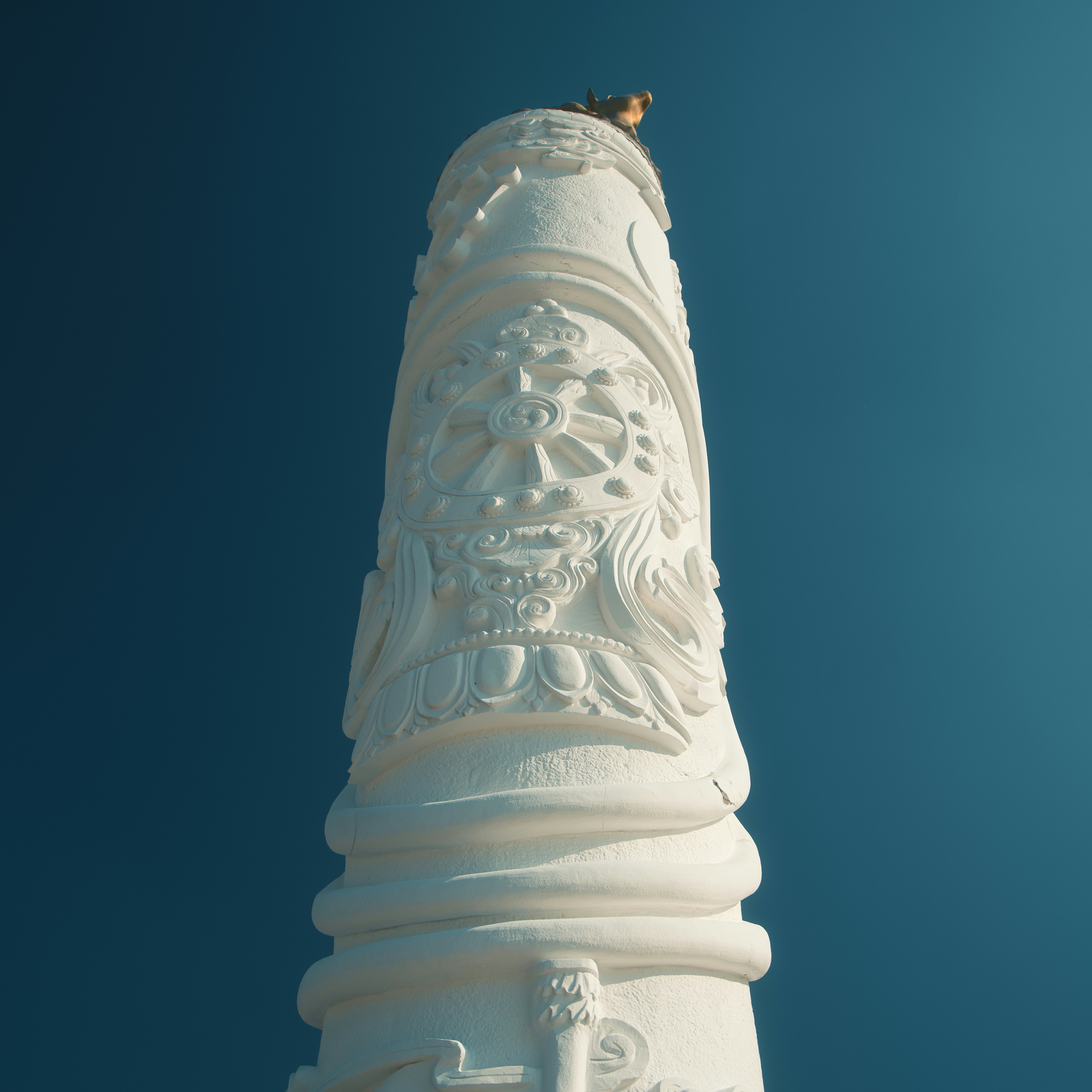 Carved Spiral Relic Reaching Toward a Blue Sky