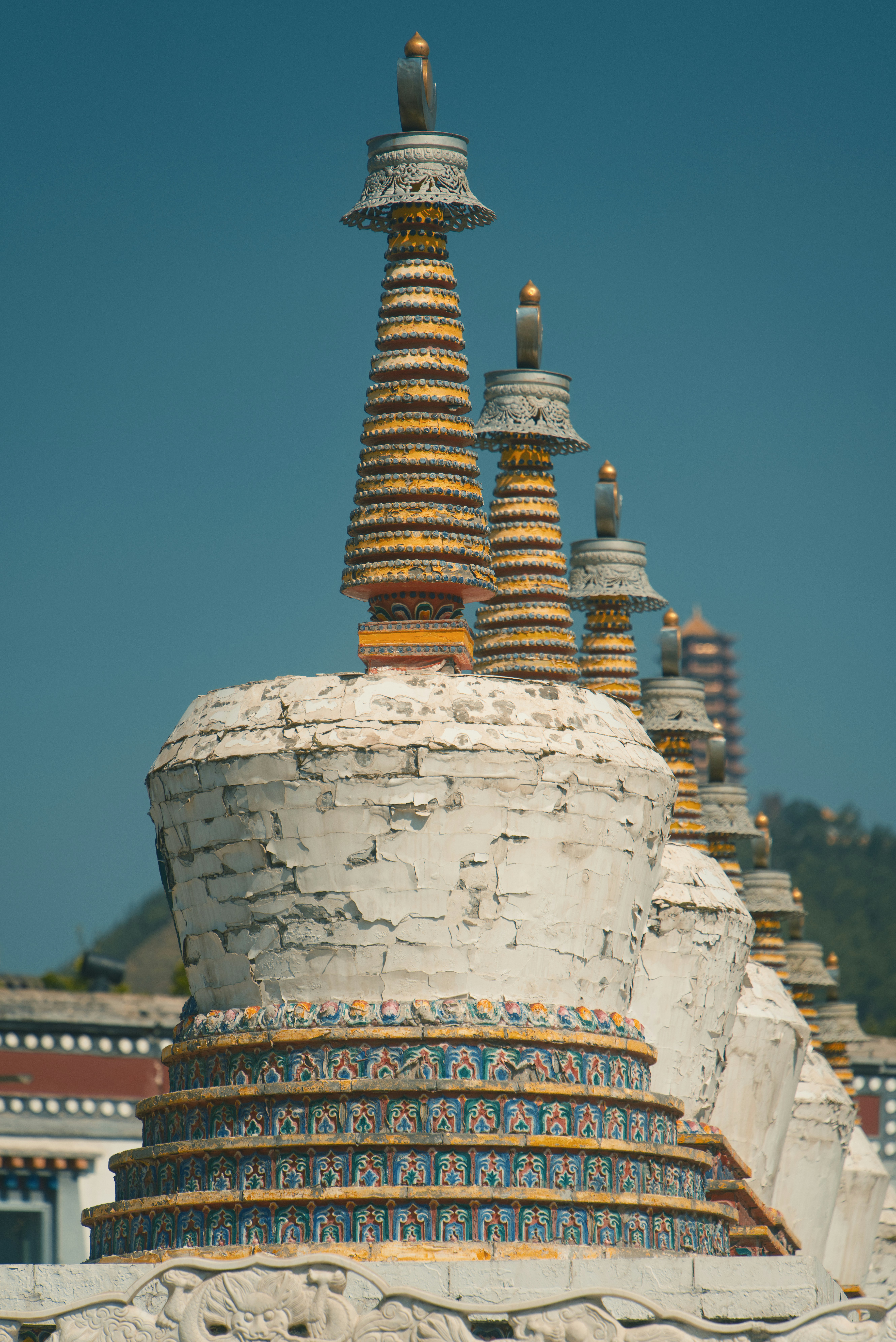 Row of ornate prayer wheels rising above weathered stupa bases