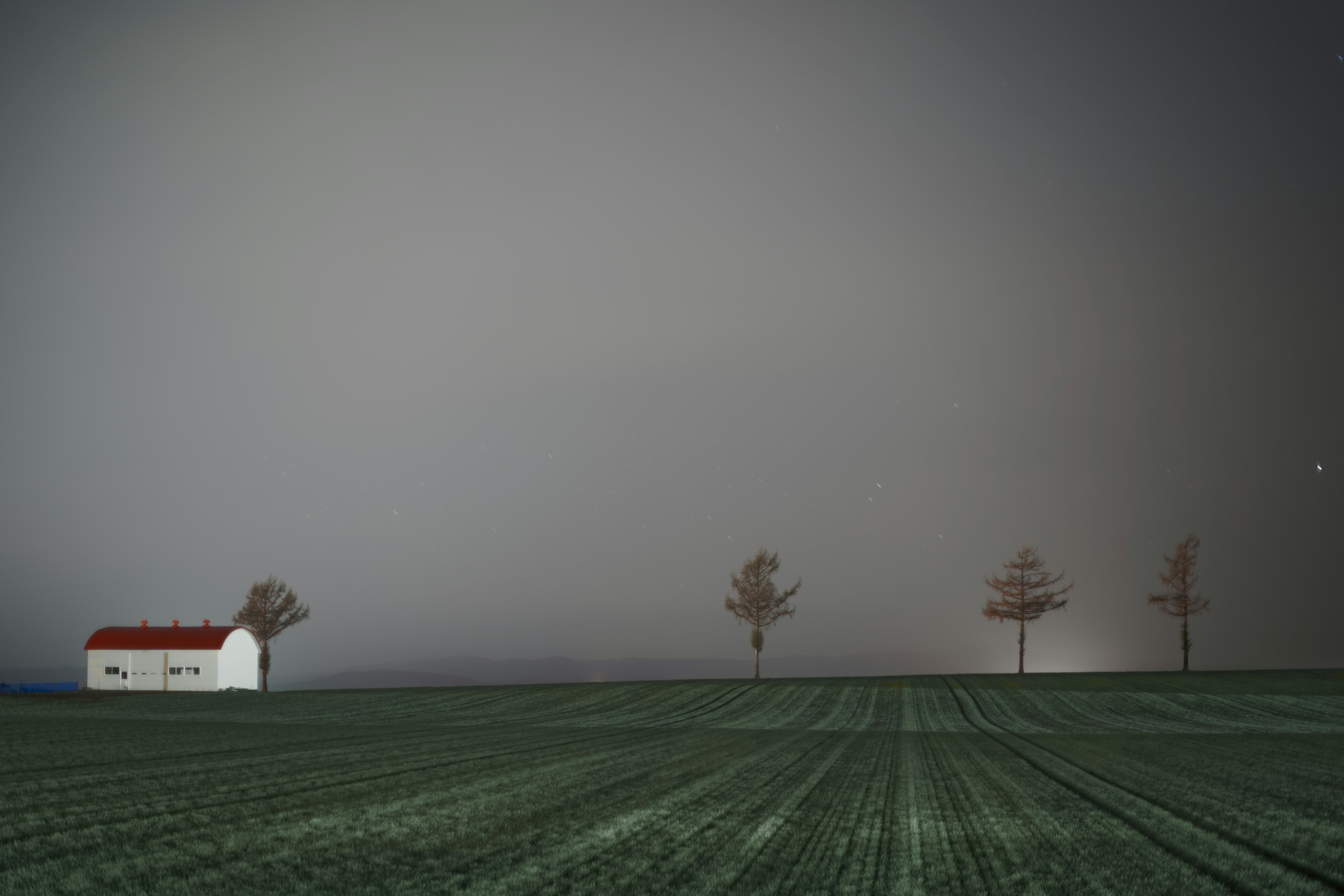 Low Sun, Quiet Farm: A Distant Homestead Against Open Fields