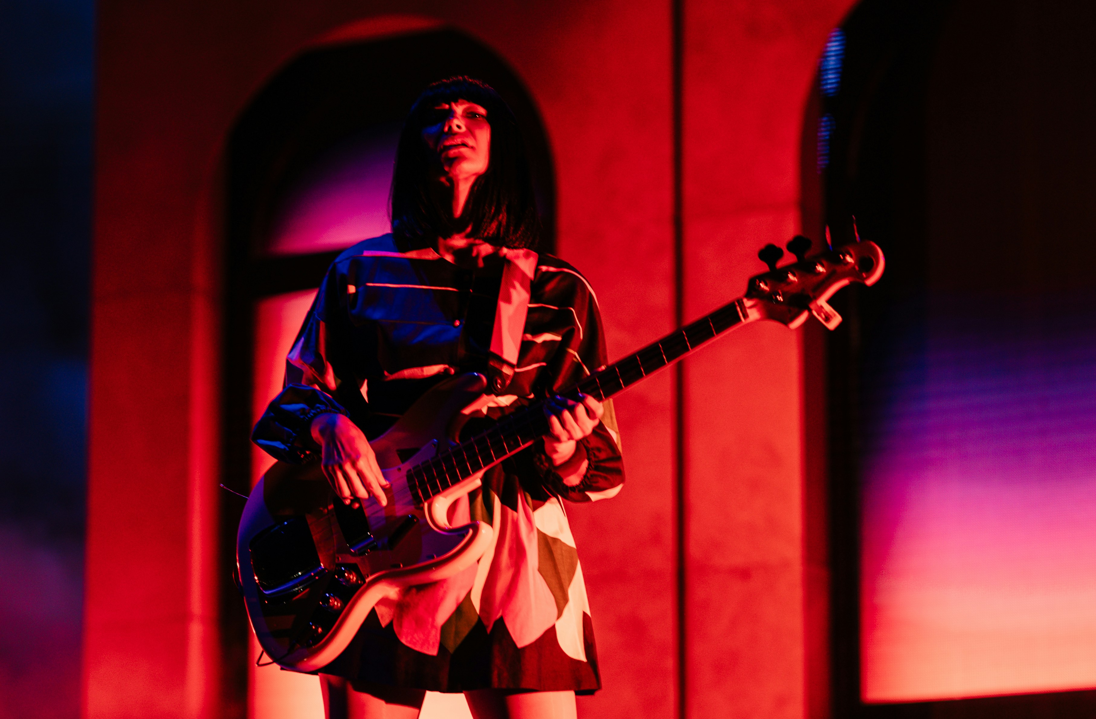 Neon-hued riffs: a neon-lit guitarist under crimson stage lights