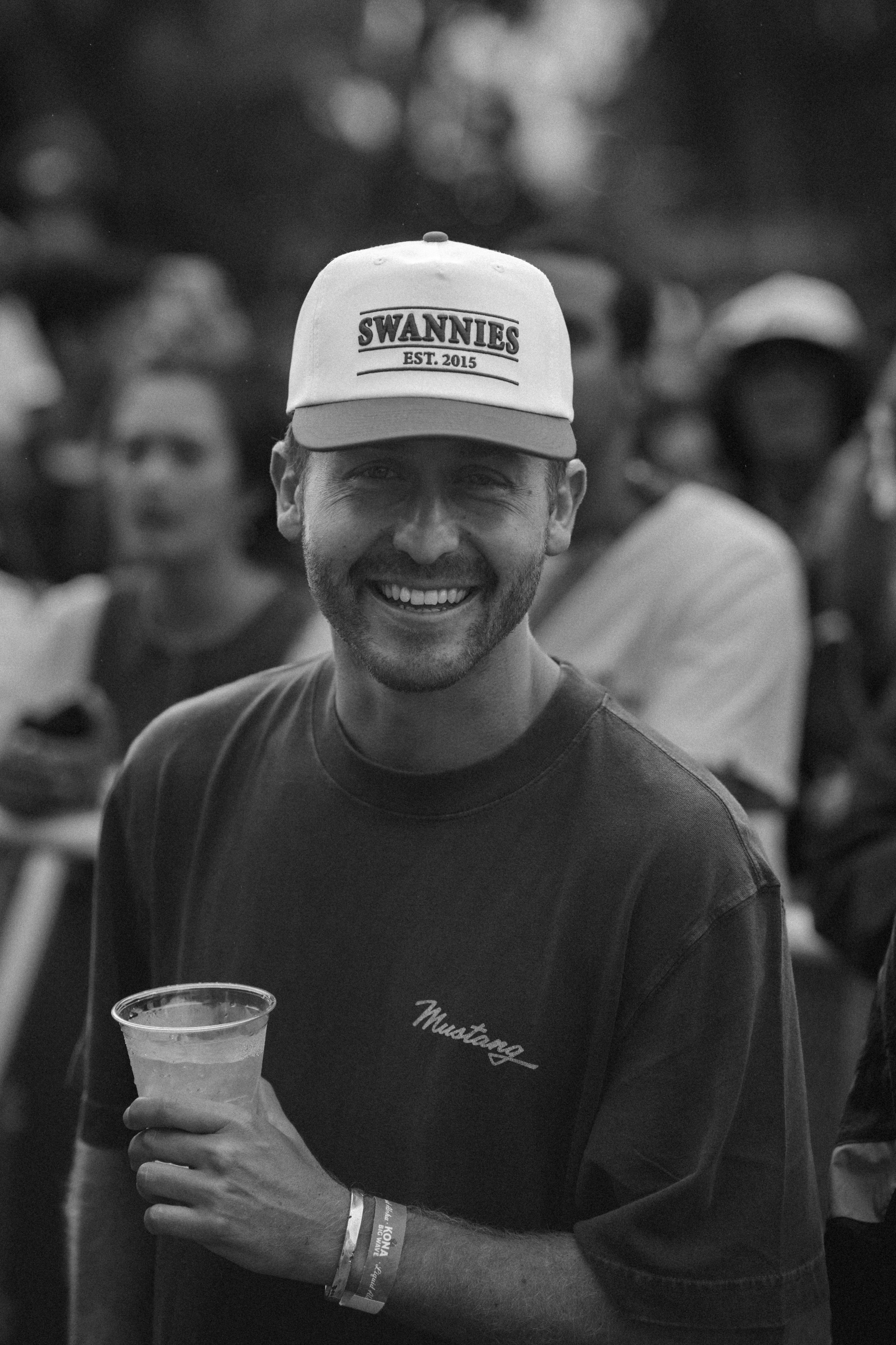 Smiling Frontman in a Crowd: Swannies Hat and Beer in Hand