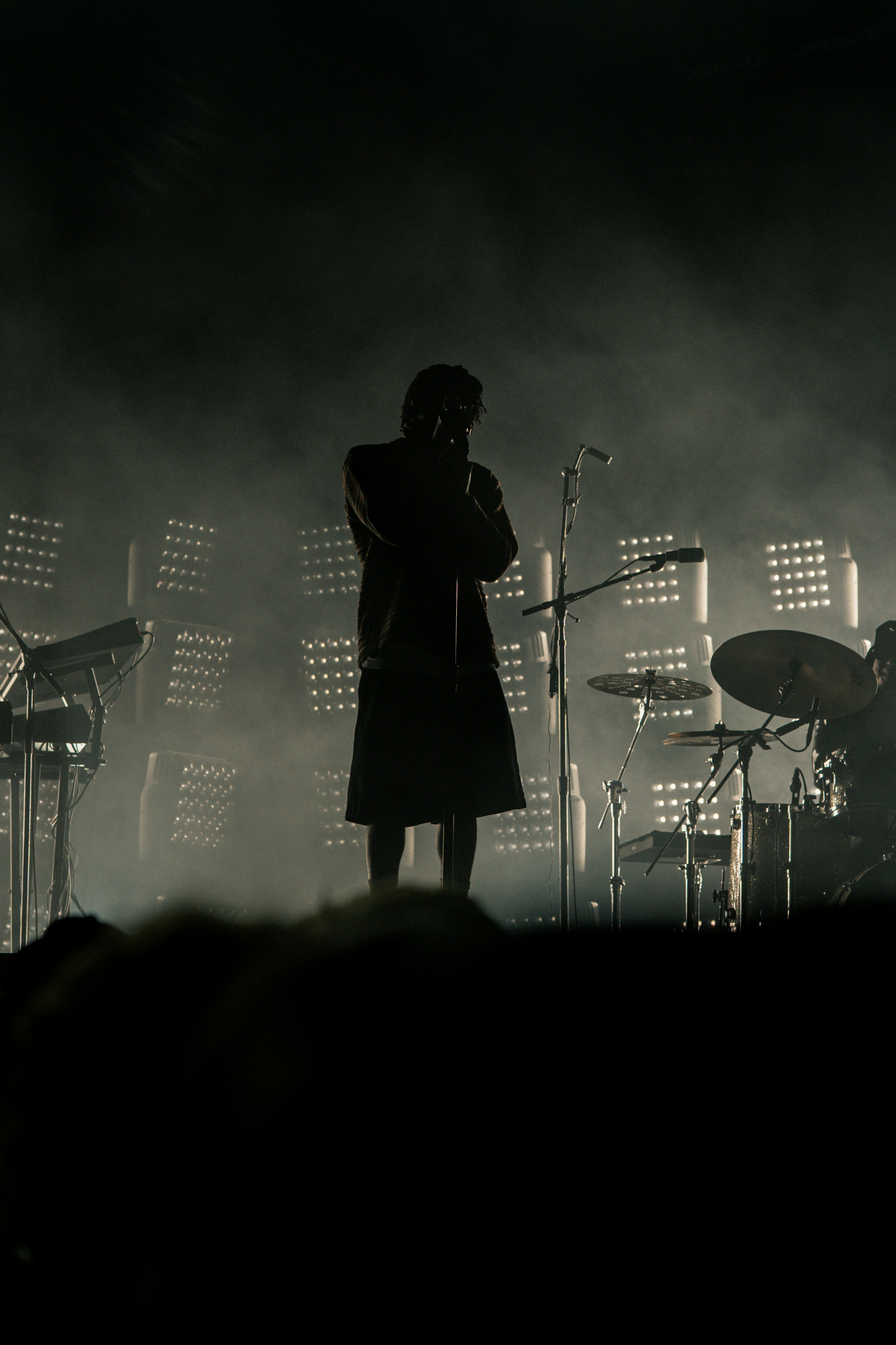 Silhouette on Stage: A Lone Figure Beneath Neon Mist