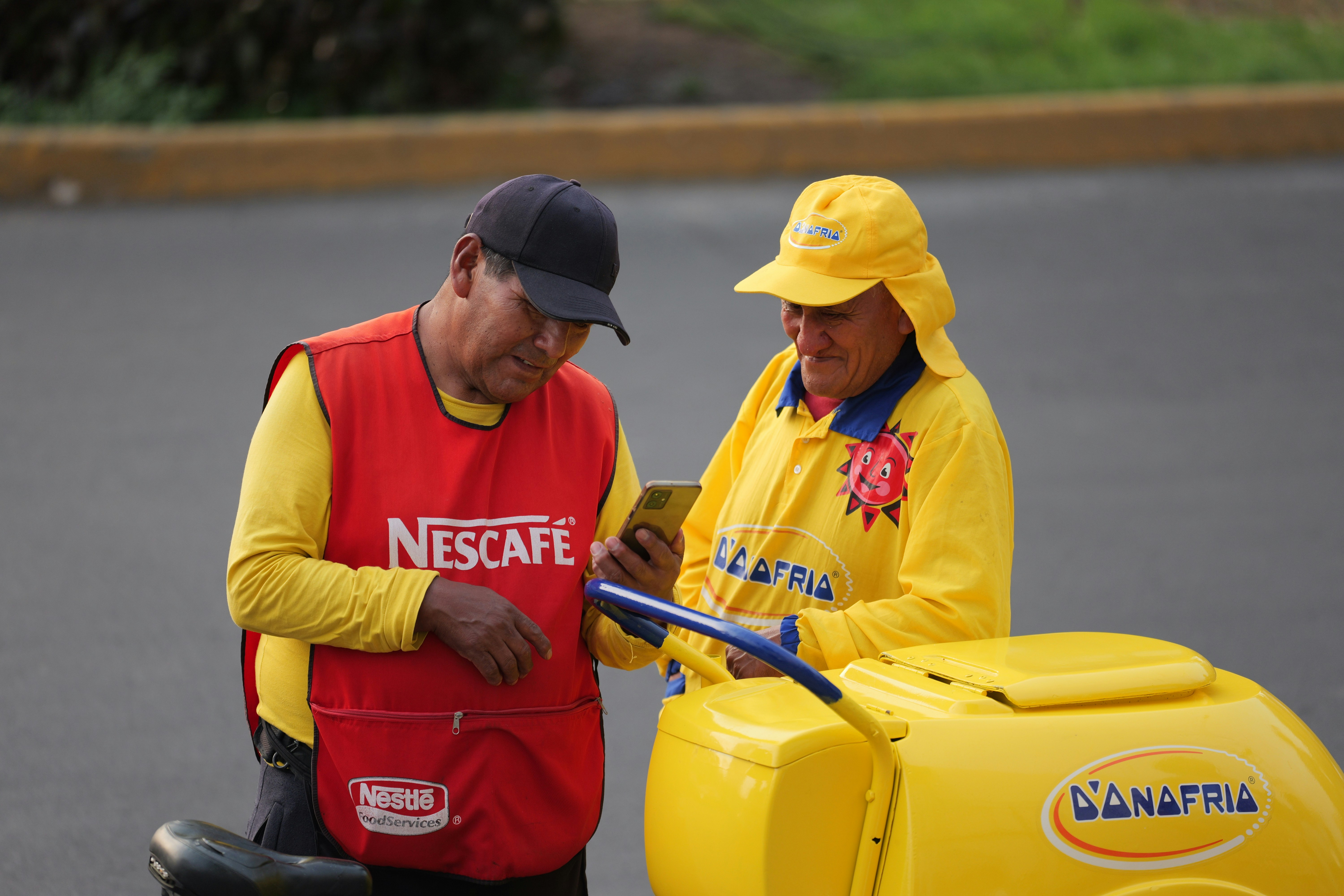 Two Vendors in Colorful Uniforms Stand Beside a Yellow Vehicle