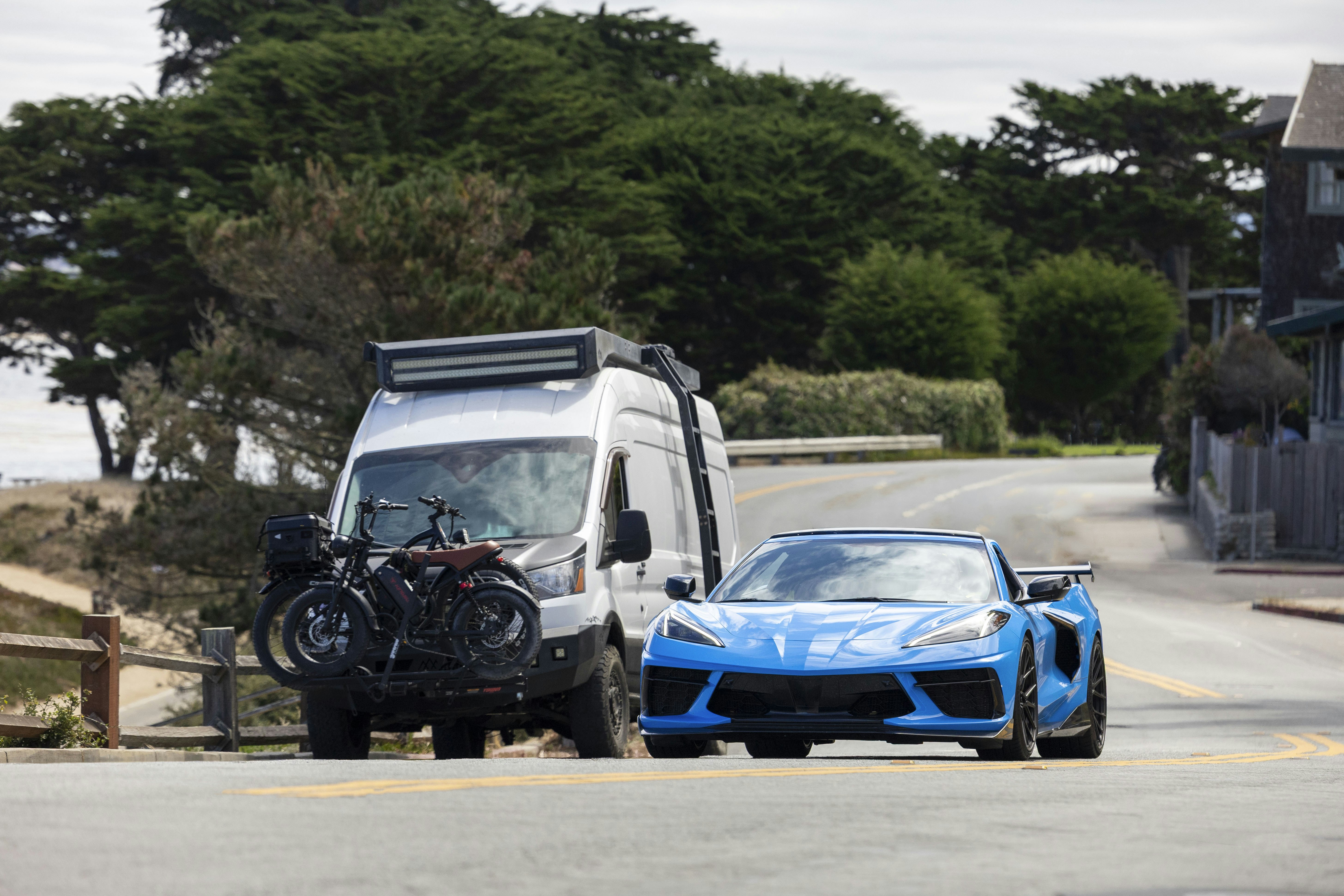 Blue Sports Car Paired with a Cargo Van on a Coastal Road