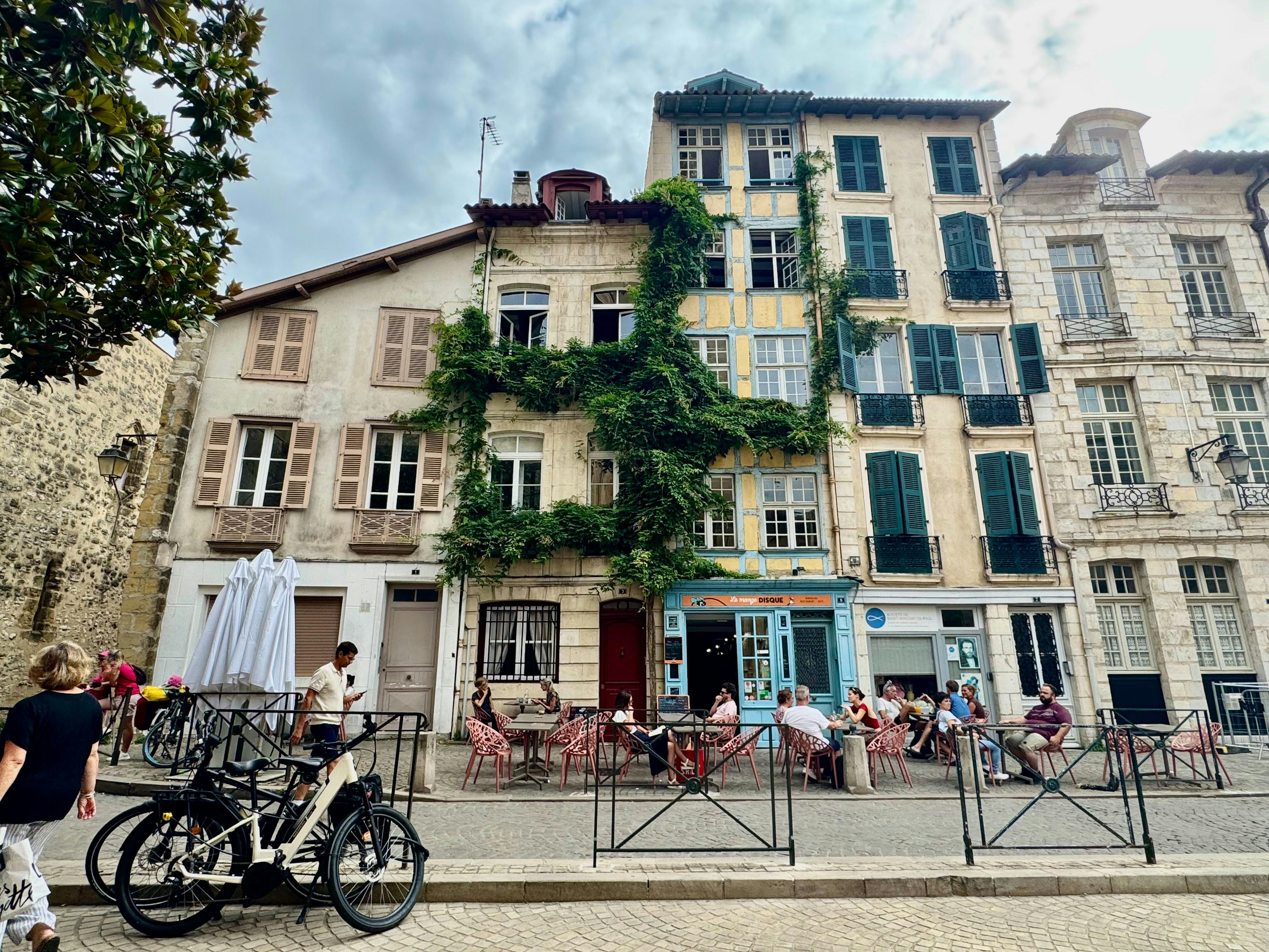 Cafés, Climbing Ivy, and Cornerstones in a Sunlit European Alley