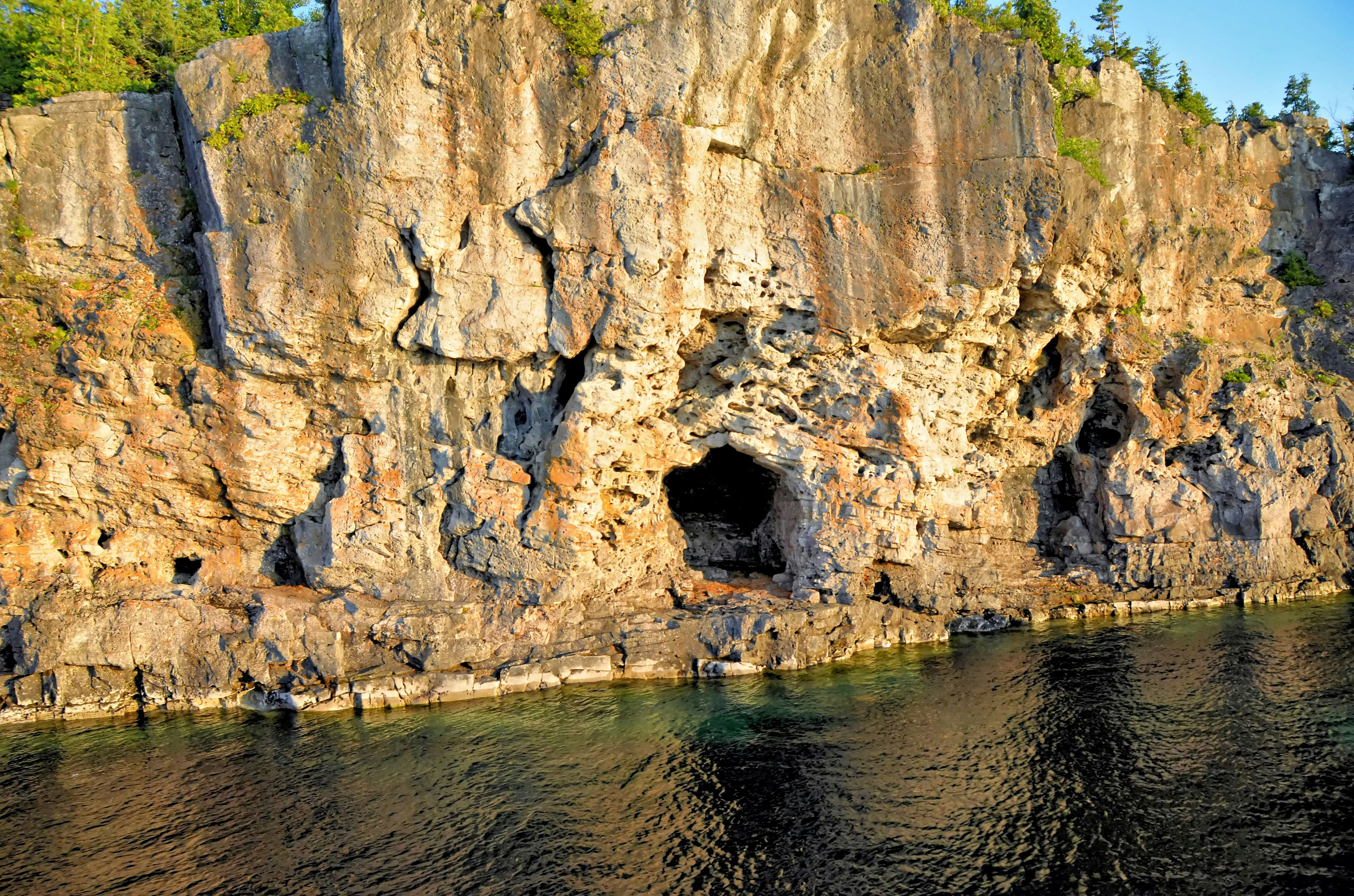 Sunlit sea cave fragments along rugged limestone shoreline