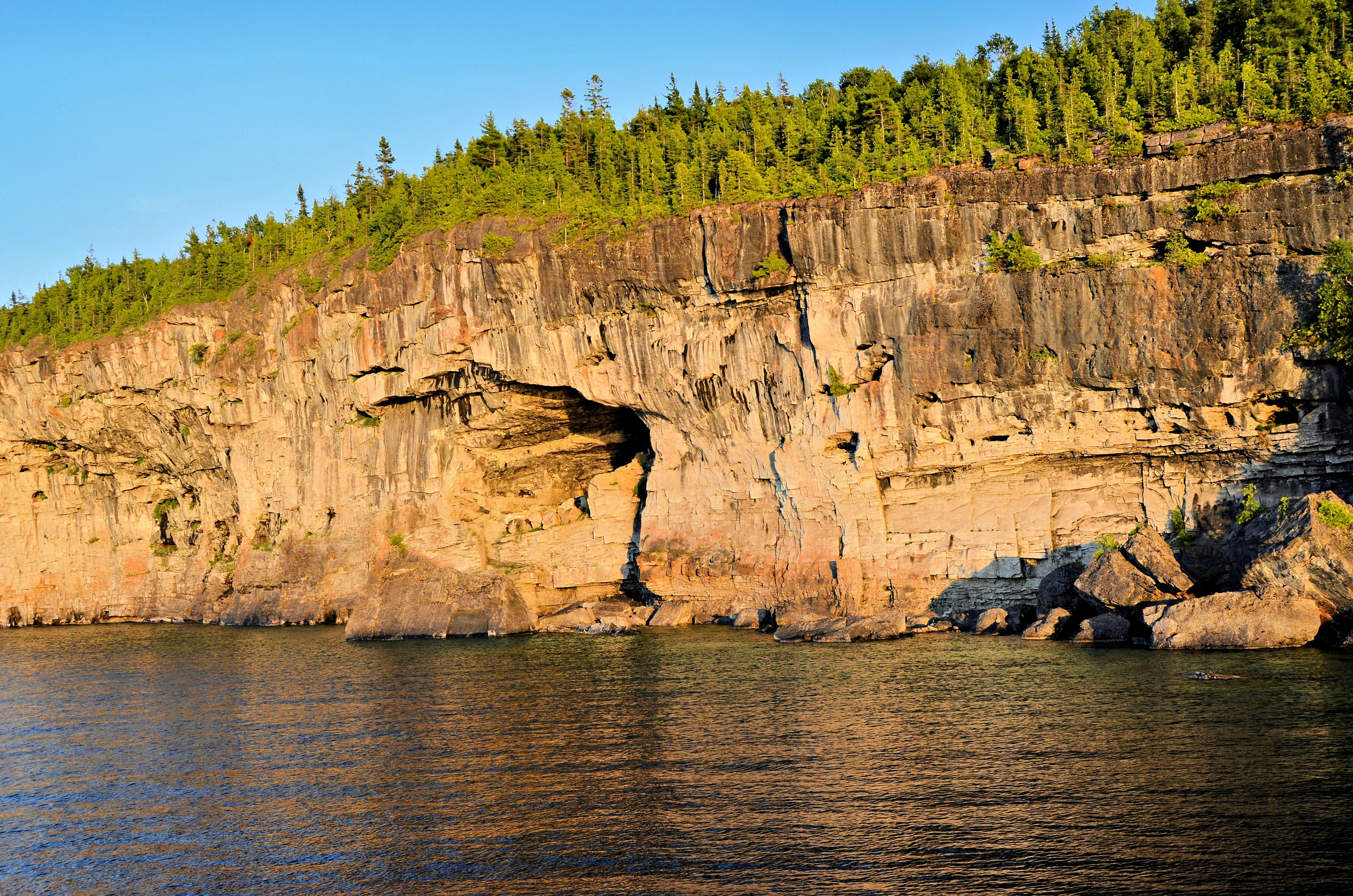 Sunlit Cliffs Over Calm Waters at Dusk
