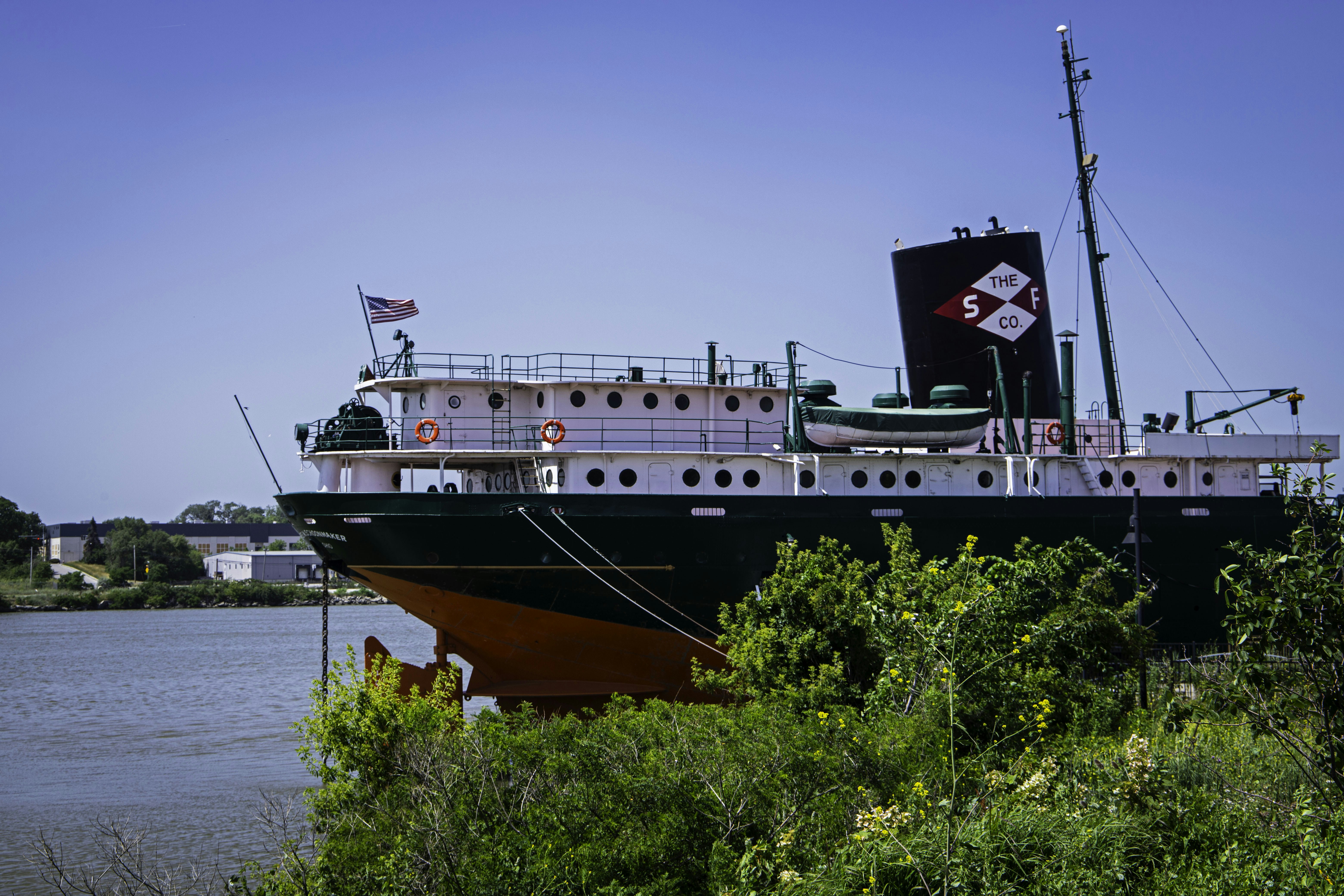 Rail-ship at the river edge: a vintage deckboat with bold red hull