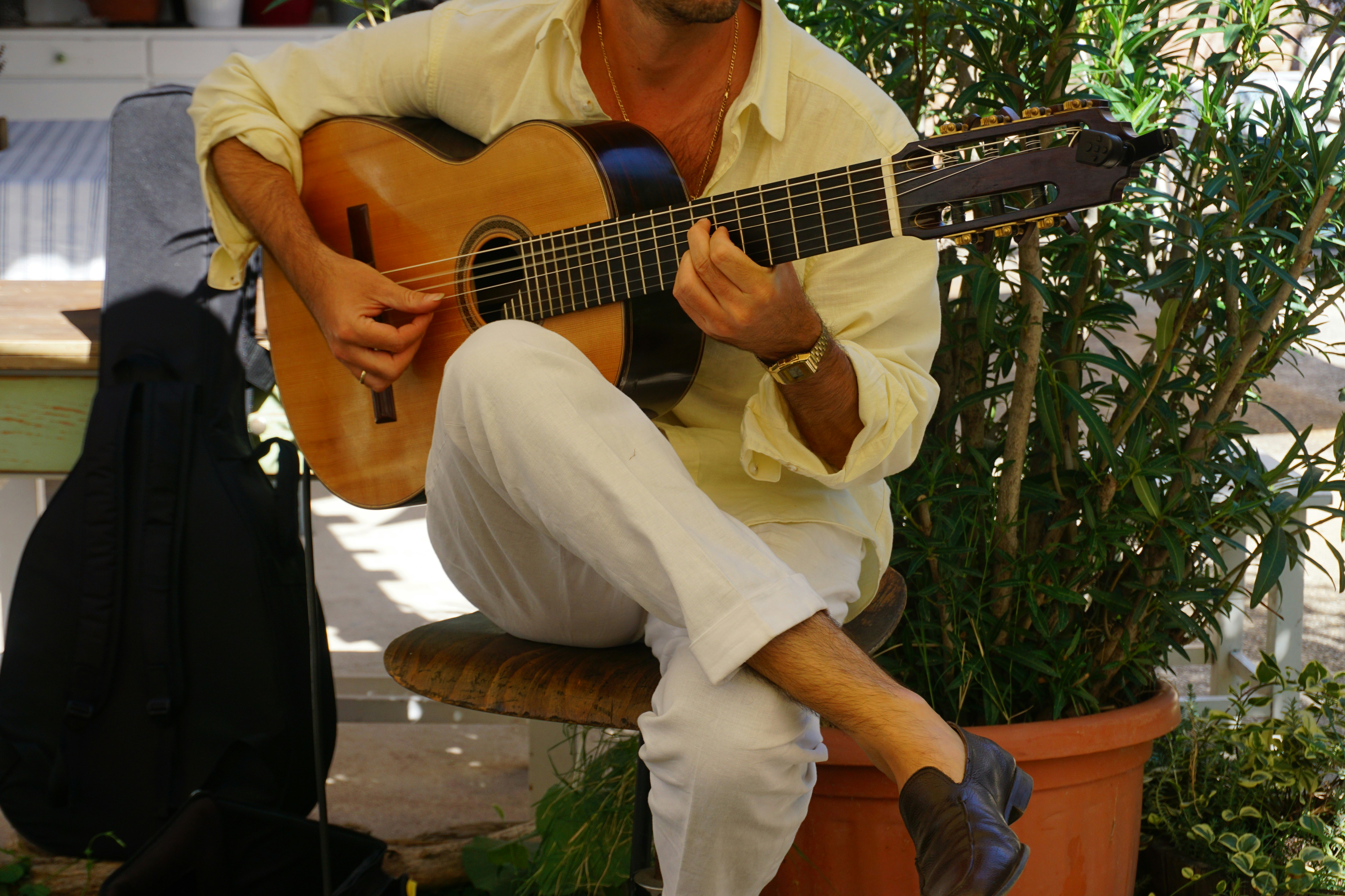 Guitarist in a sunlit patio: casual performance with a classical cutaway