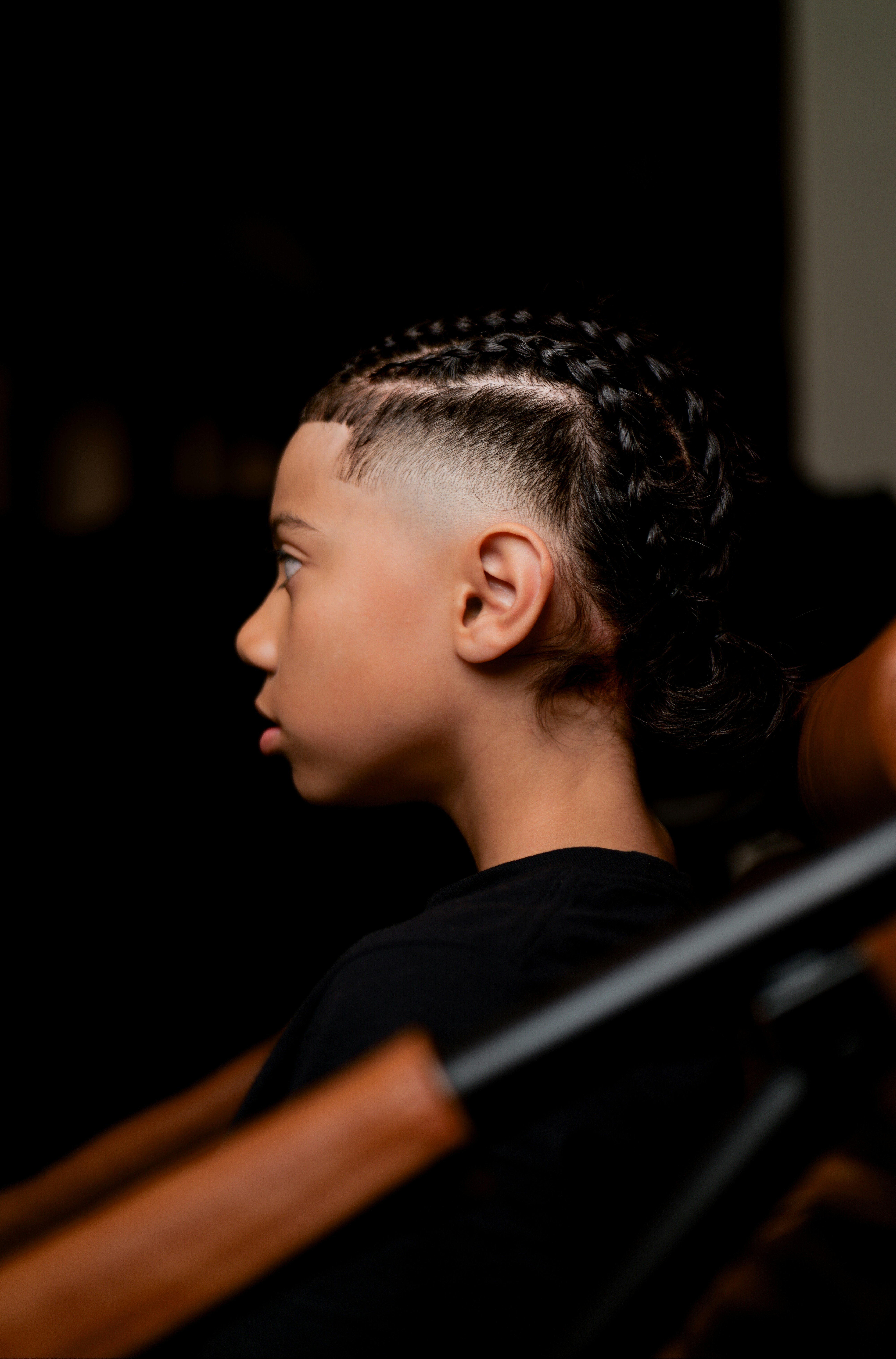 Profile of Confidence: A Youthful Portrait with Braided Hair and Defined Fade