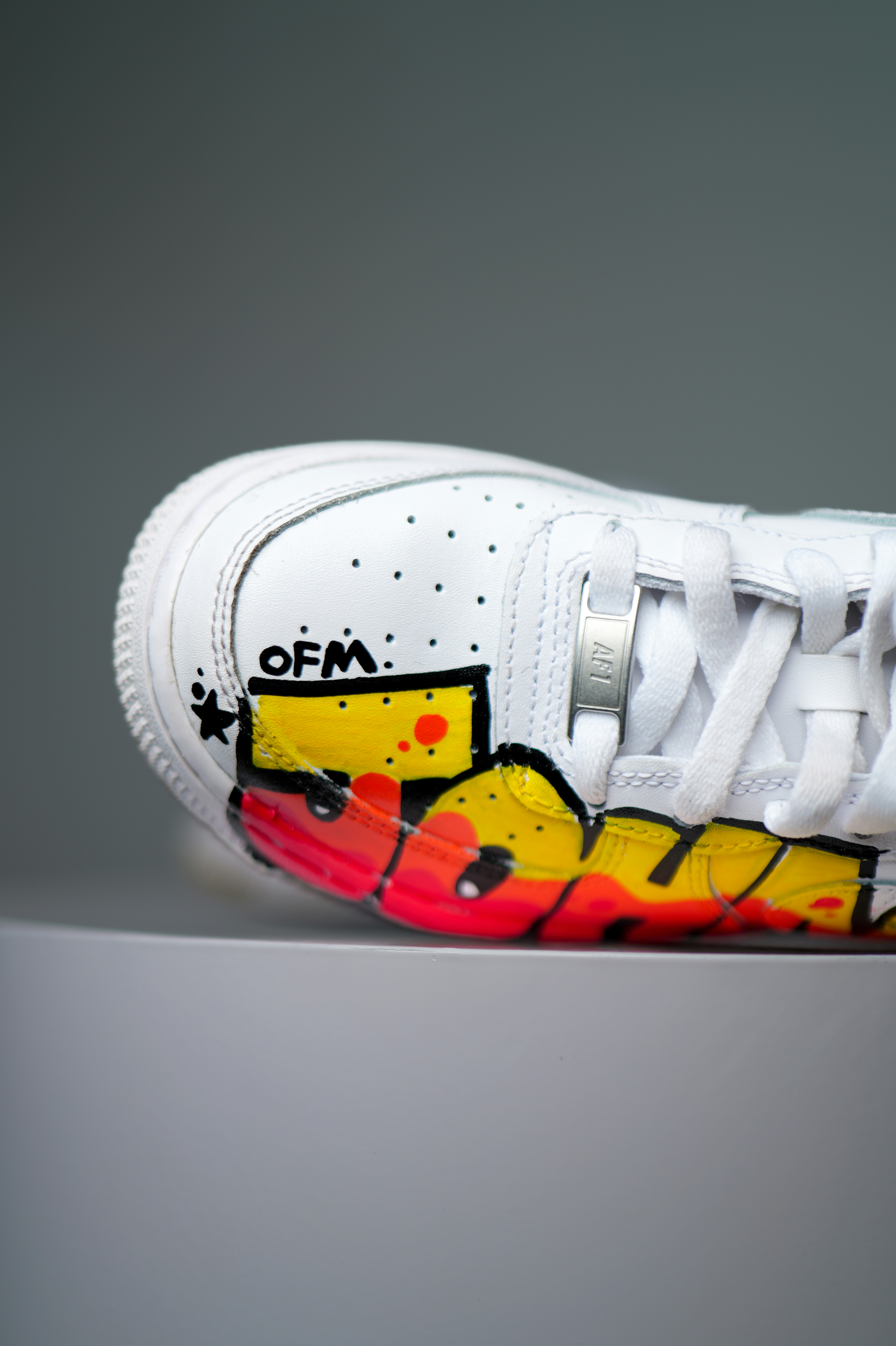 Graffiti-Led Sneaker: White Sneaker with Colorful Artwork Resting on a Surface