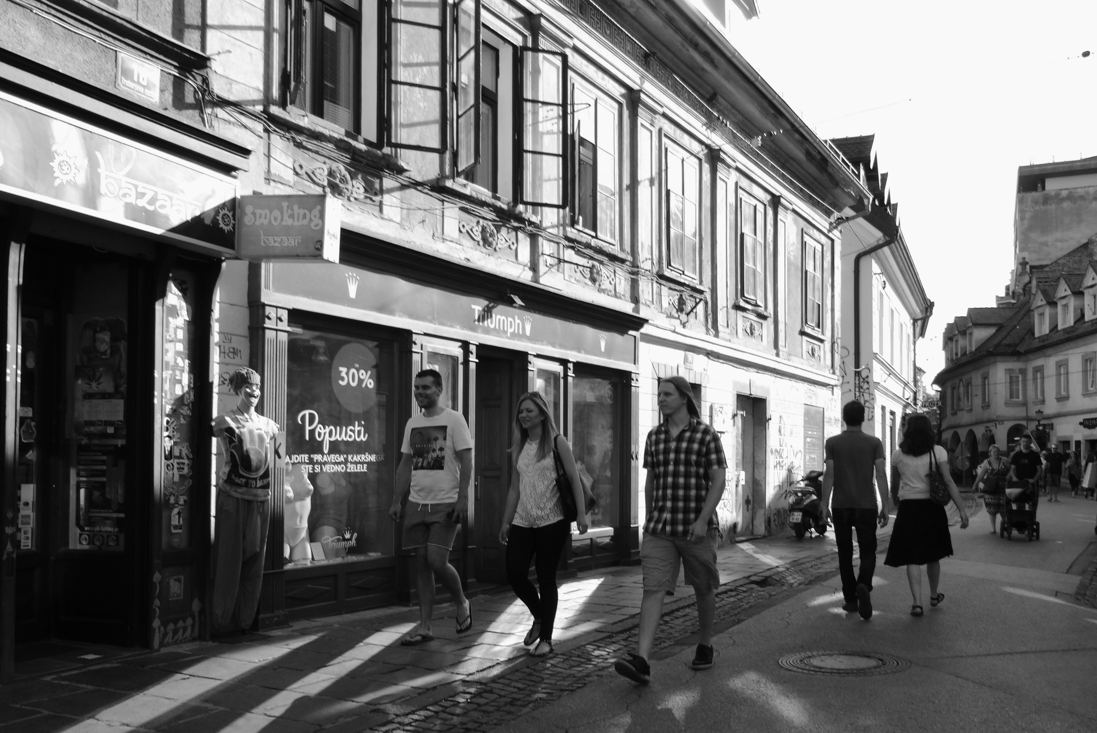 Pedestrians Walk Past Shopfronts in a Quiet European Street