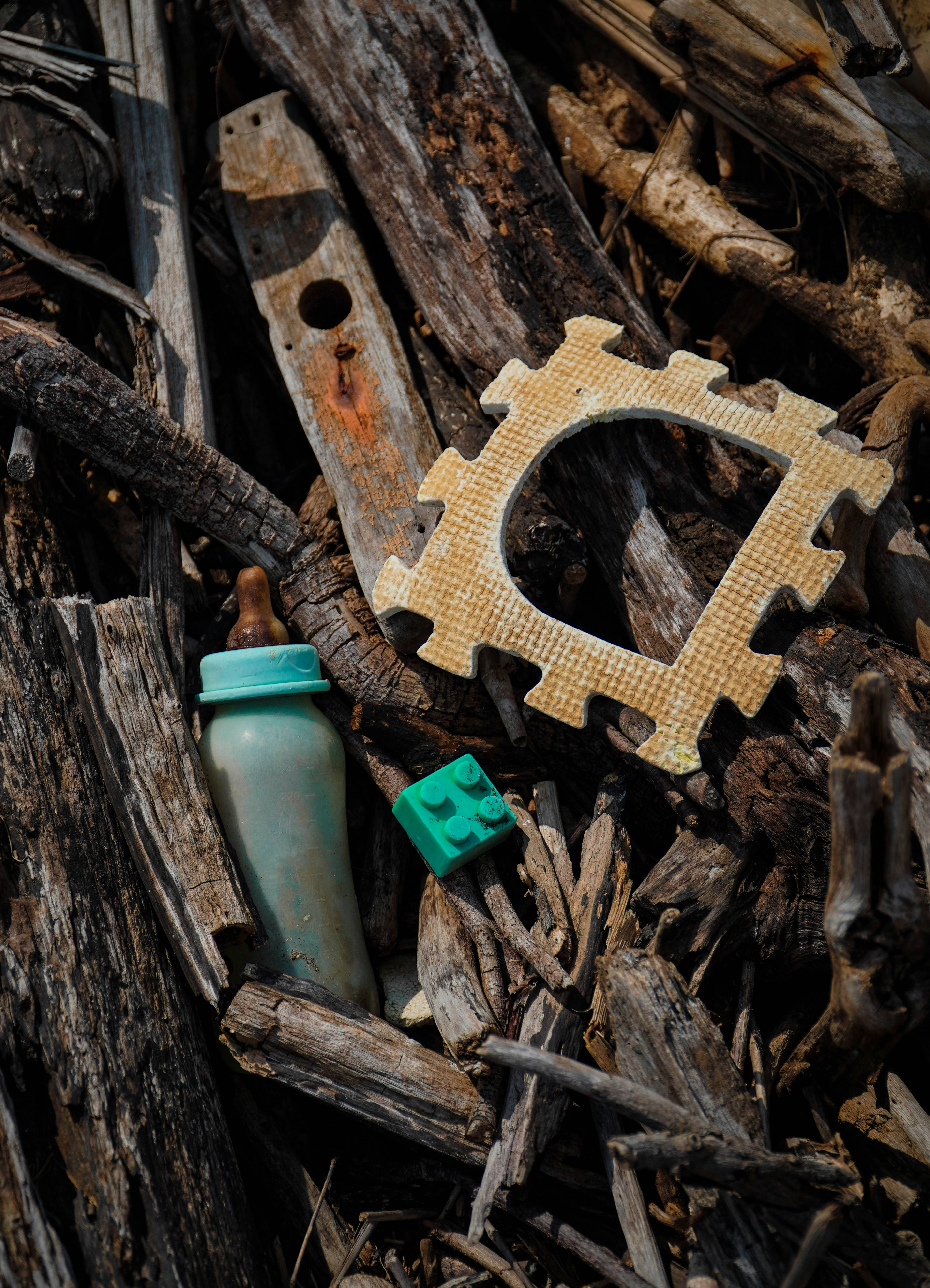 Curious Debris: A Green Bottle Cap and Gear Slice Among Charred Wood