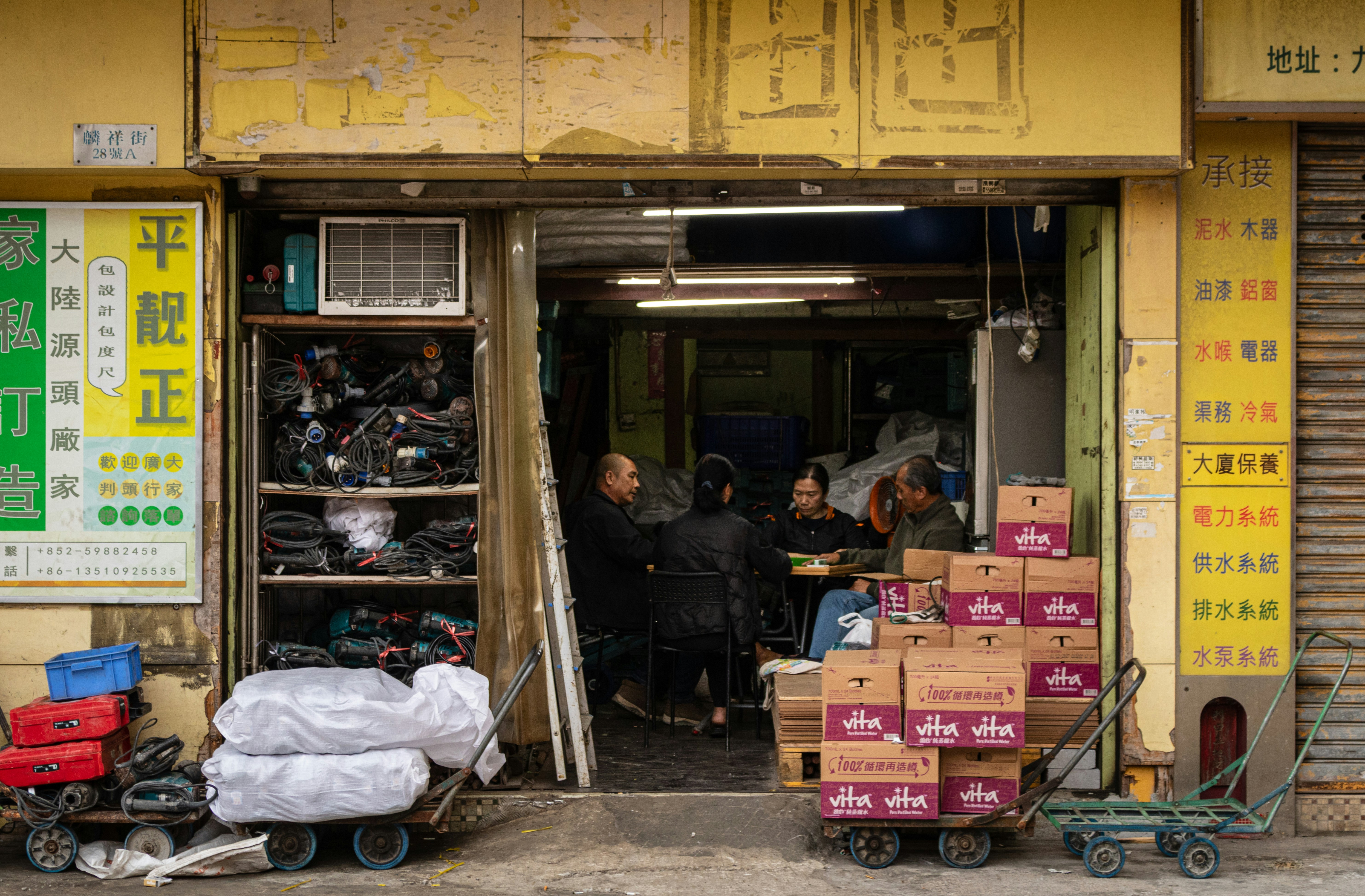 Market Workshop: Hands at the Table Amidst Spare Parts and Stacked Boxes