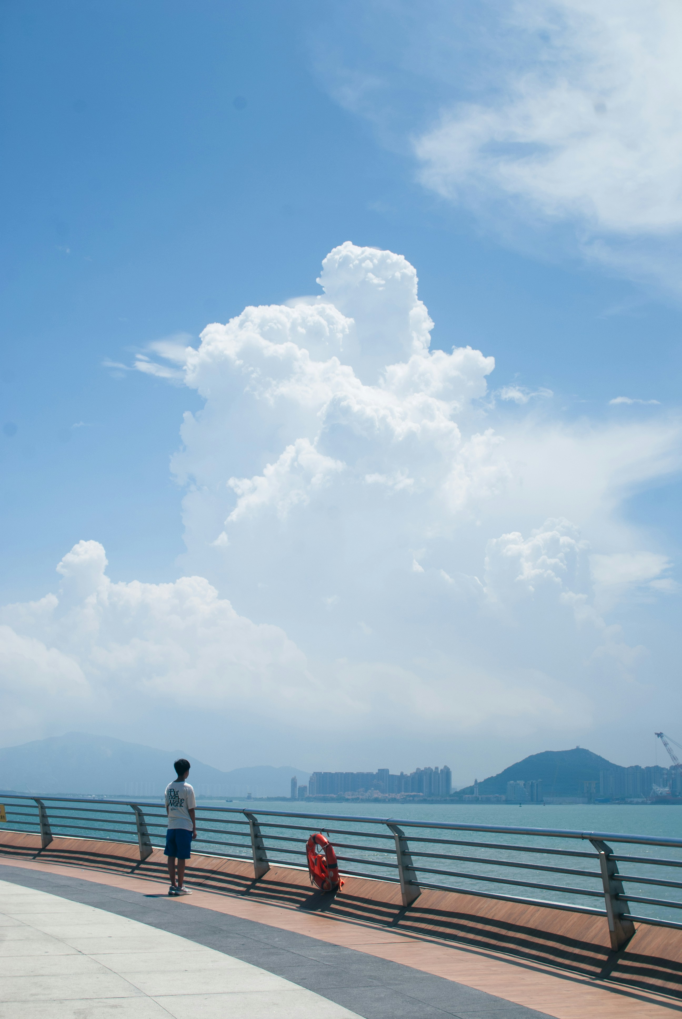 Seafront Silhouette: A Lone Pedestrian Gazes Toward Cloudscape
