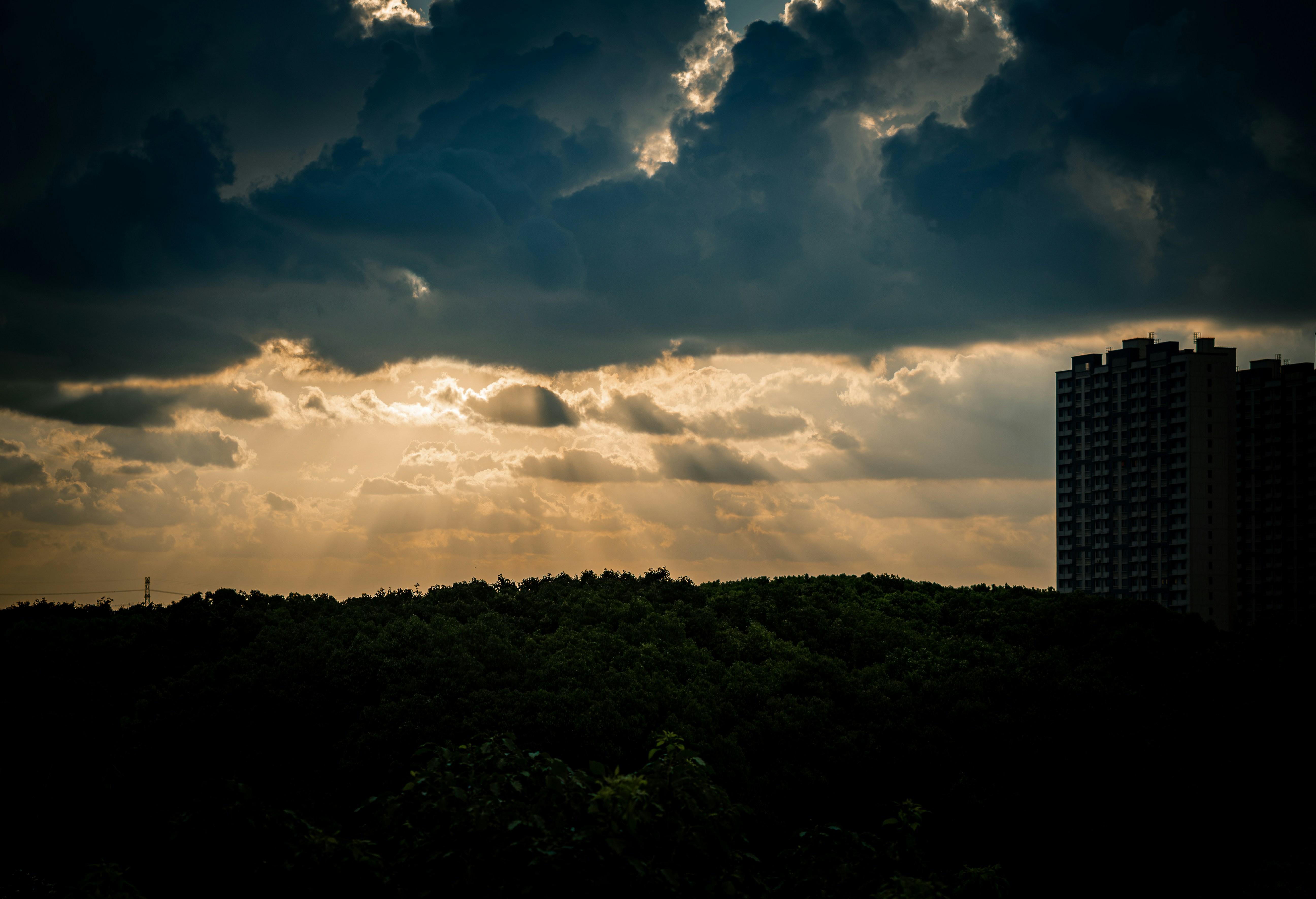 Dusk Over the Edge: Sunbeams Break Through Storm Clouds Above City Rim