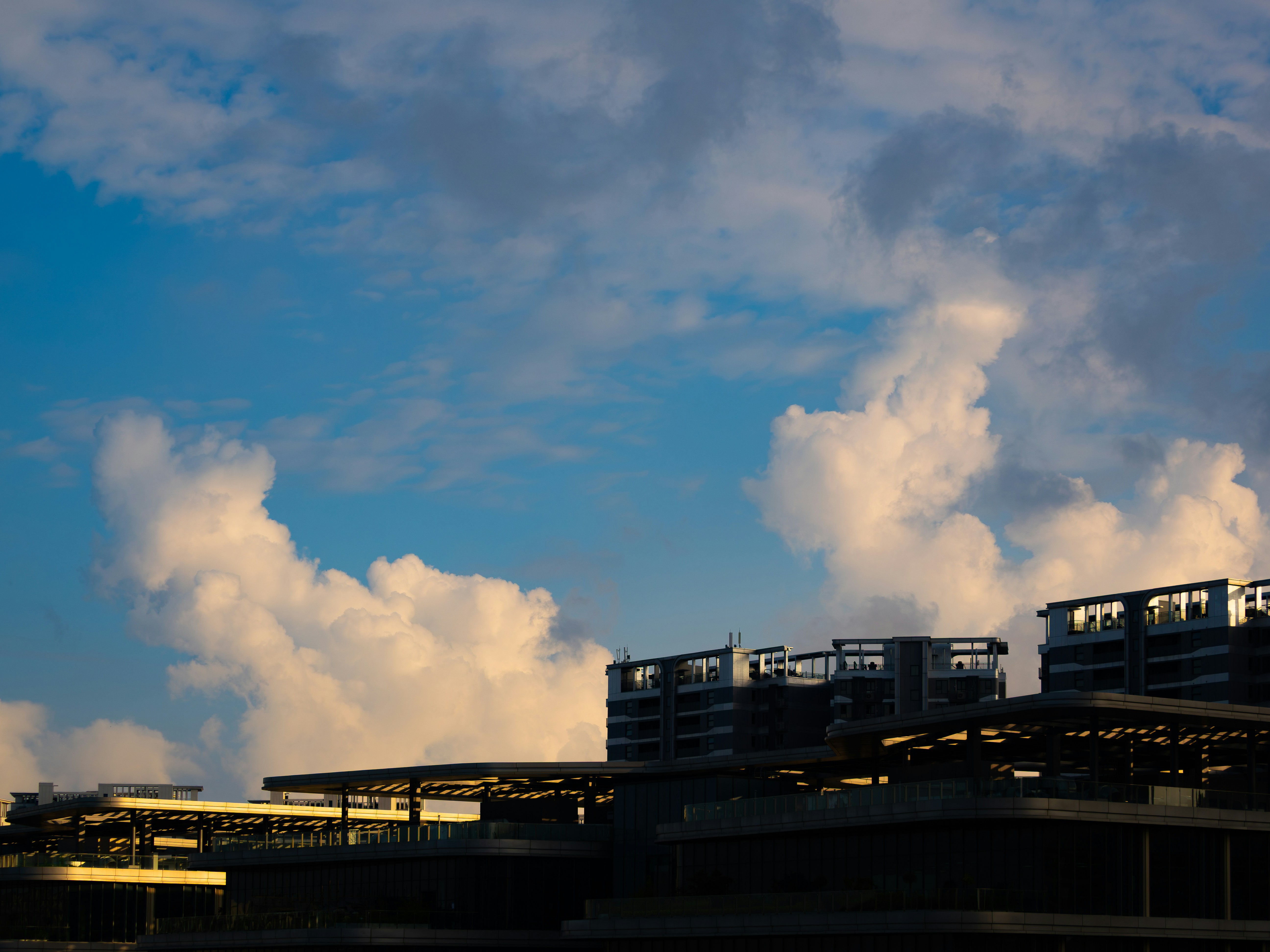 Golden Hour Overhangs: Skyline Quiet Under Puffy Clouds
