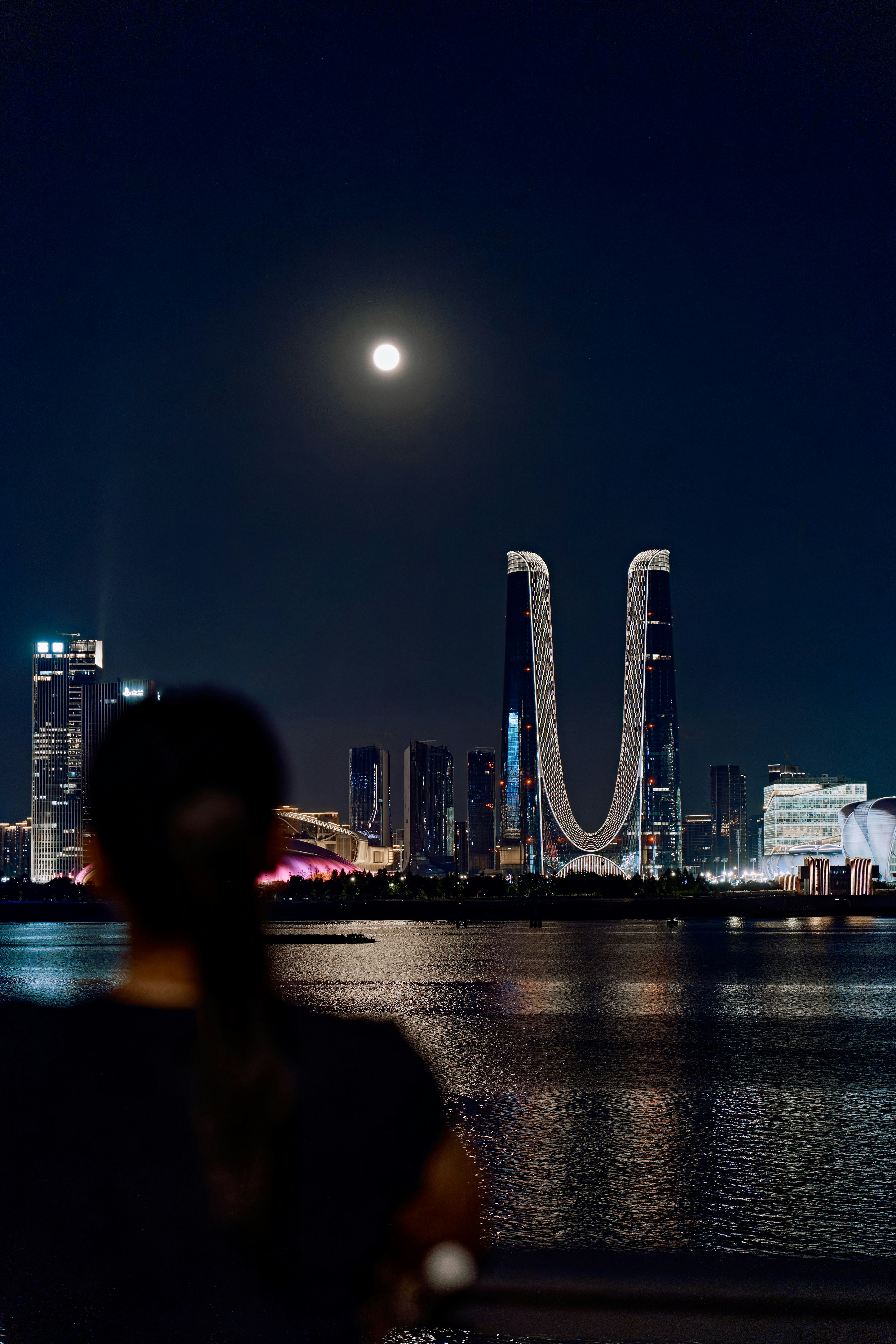 Moonlit skyline: silhouette and iconic U-shaped towers over a reflective harbor