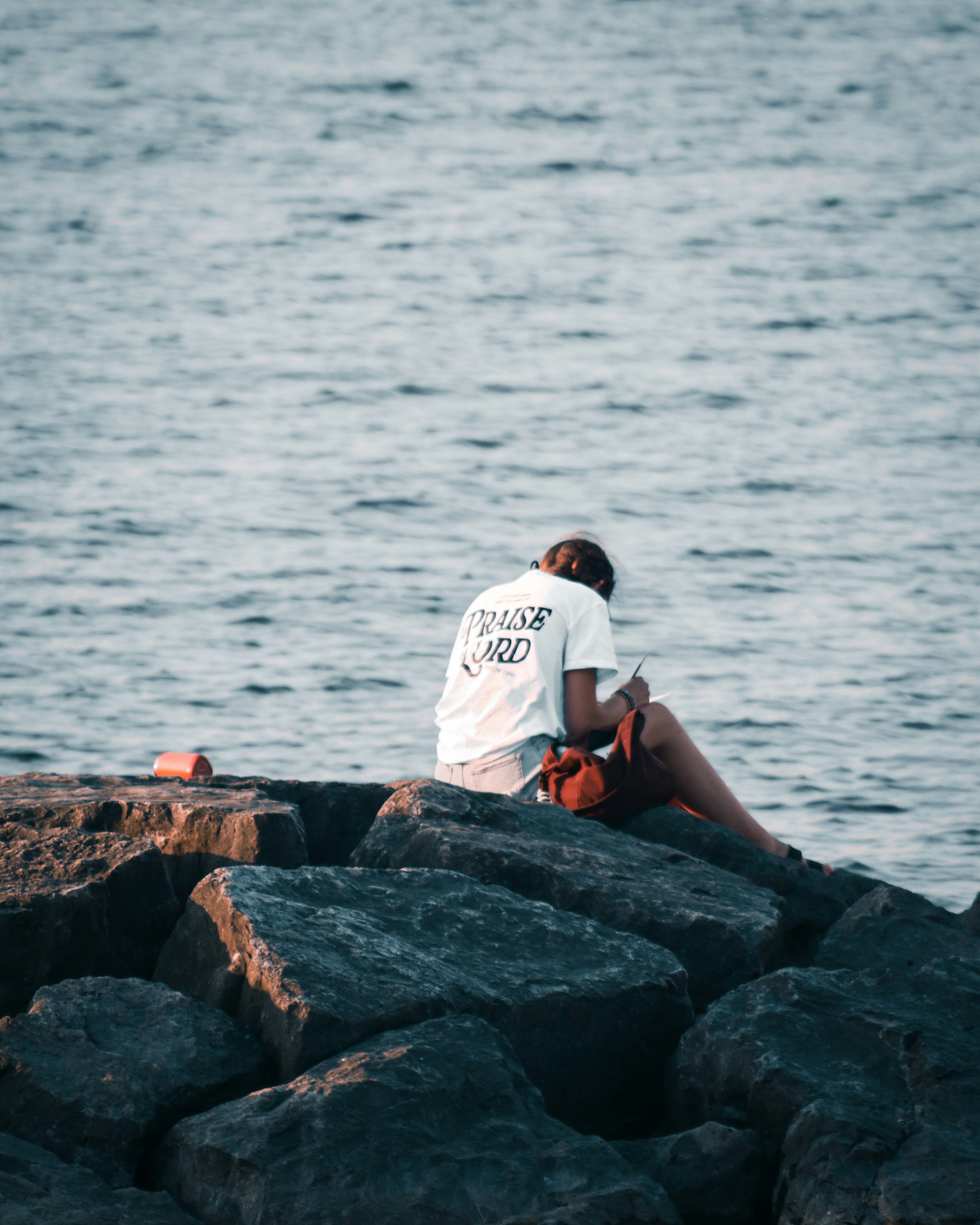 Coastal Break: Someone Lost in the Moment on Weathered Rocks