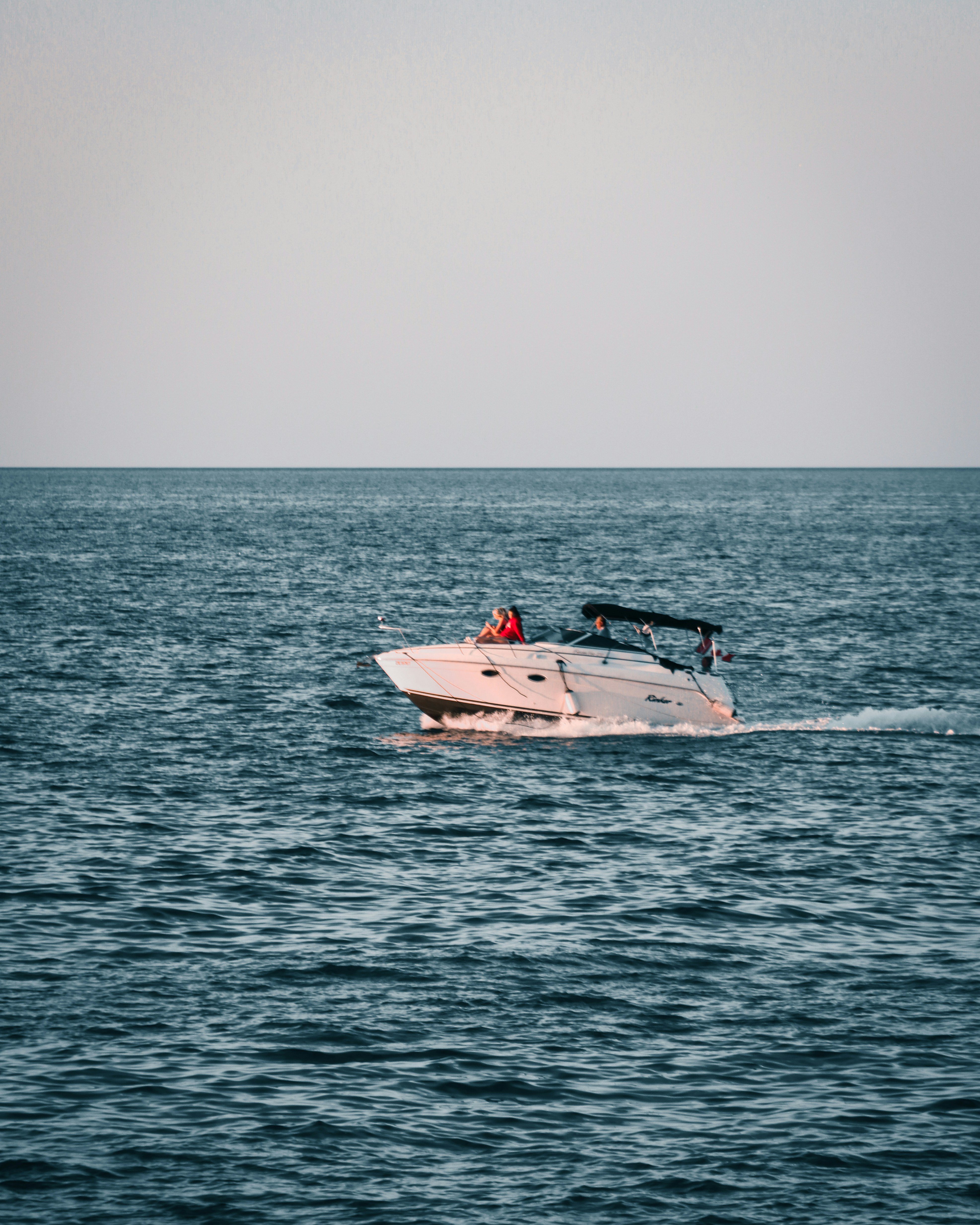 White speedboat slicing the calm blue horizon