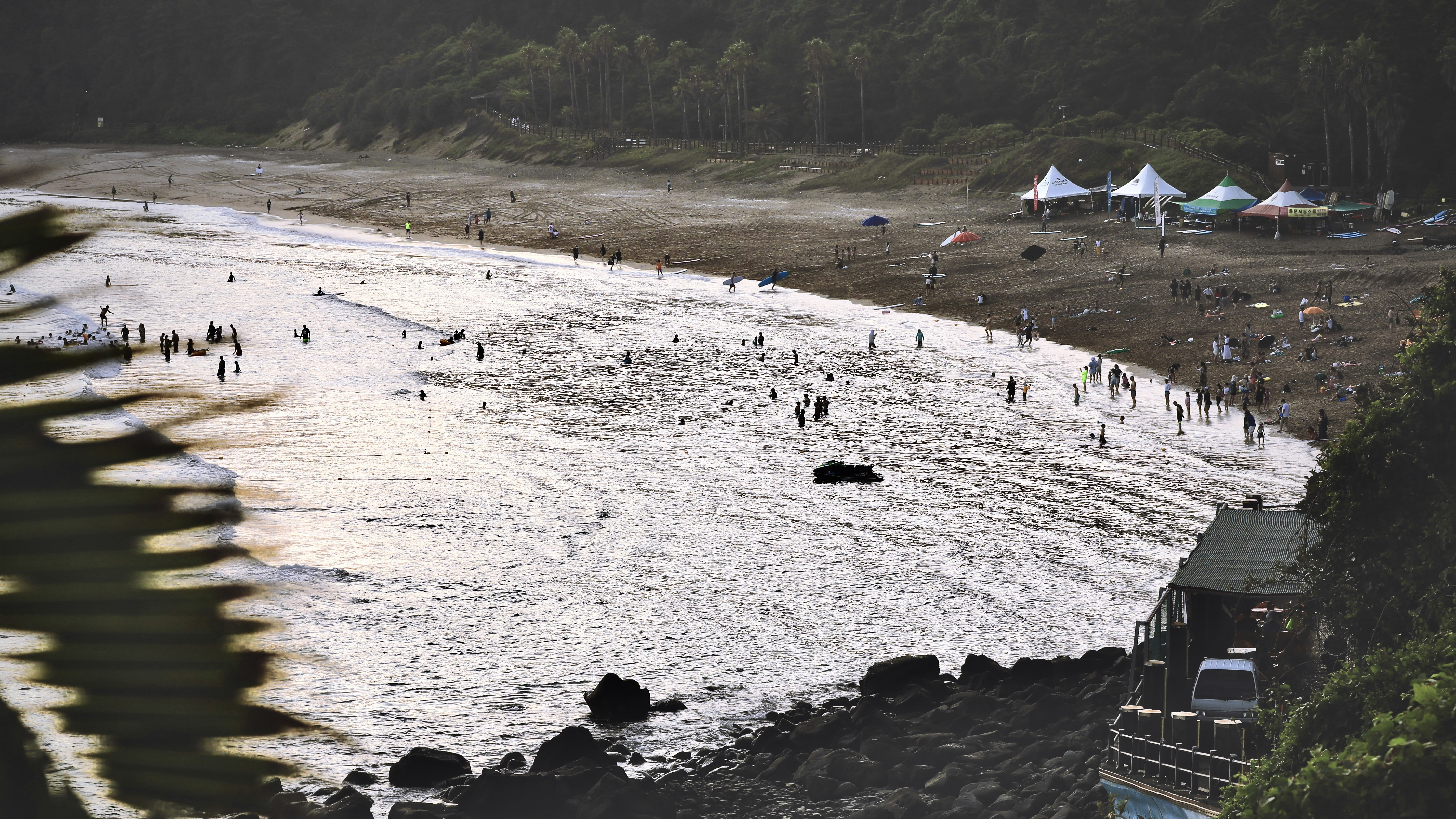 Sunlit Shoreline: People and Tents Framing a Busy Beach Scene