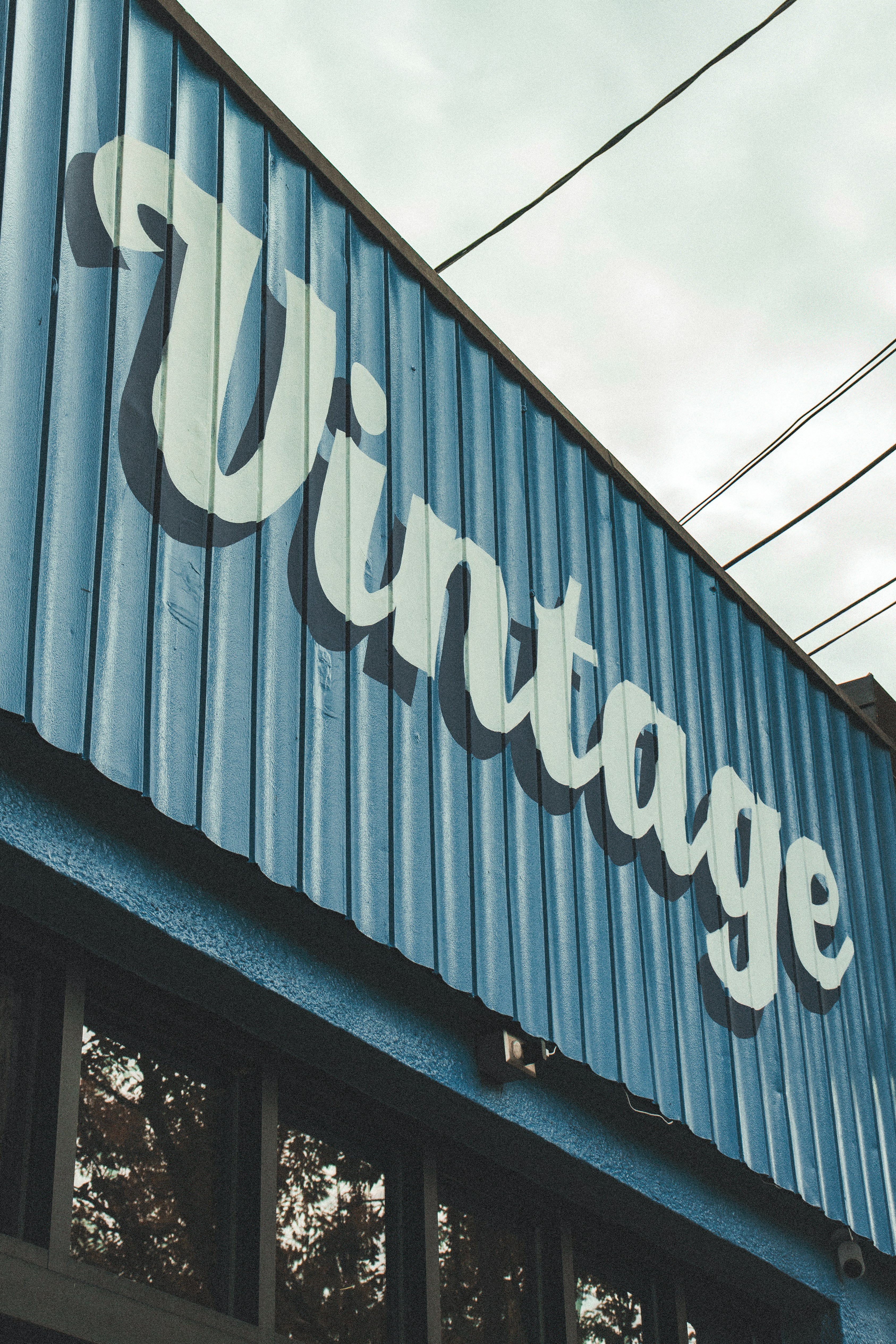 Vista of a blue corrugated storefront sign with cursive 'Vintage'