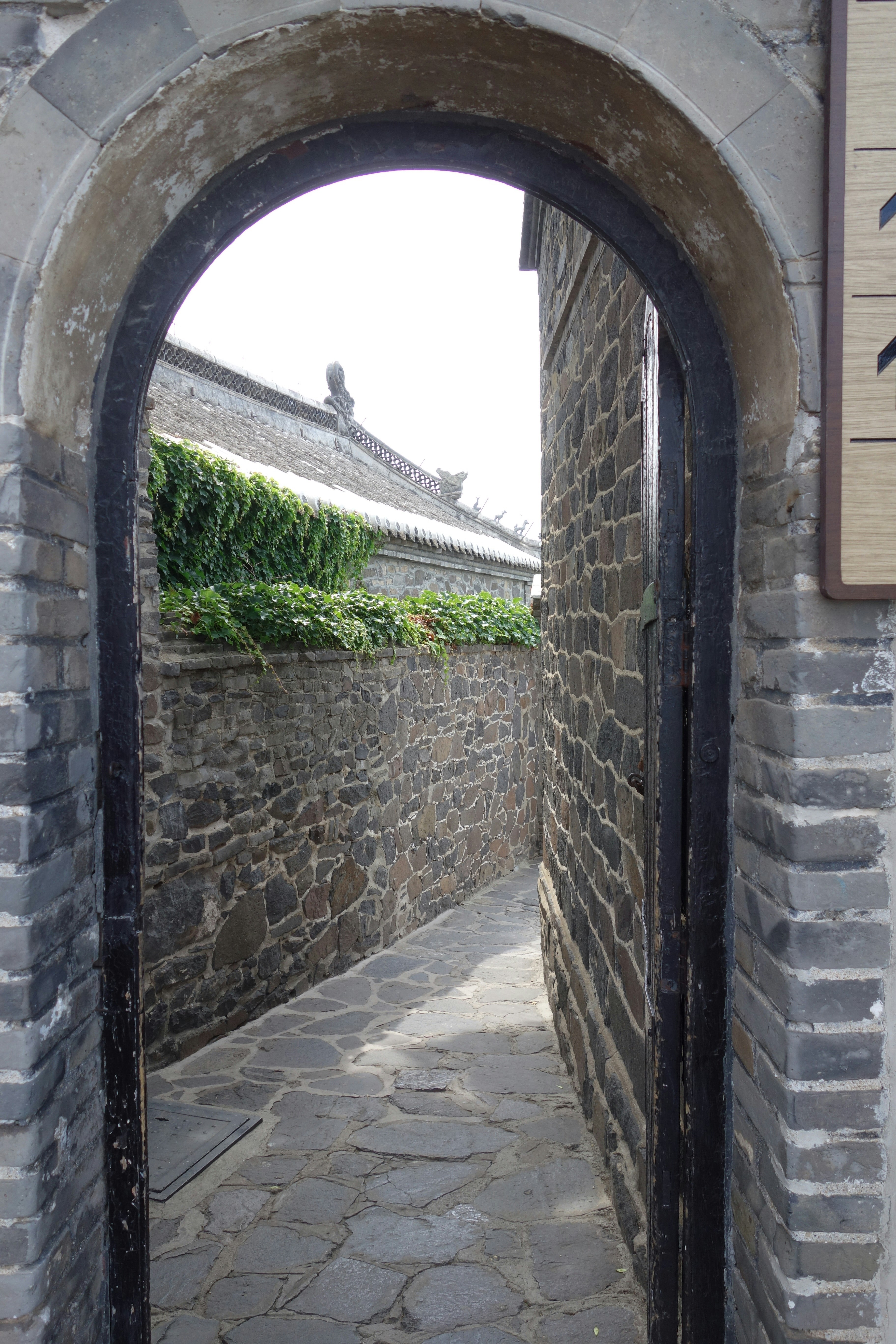 Through the Arch: A Cobblestone Corridor Framed by Stone and Ivy