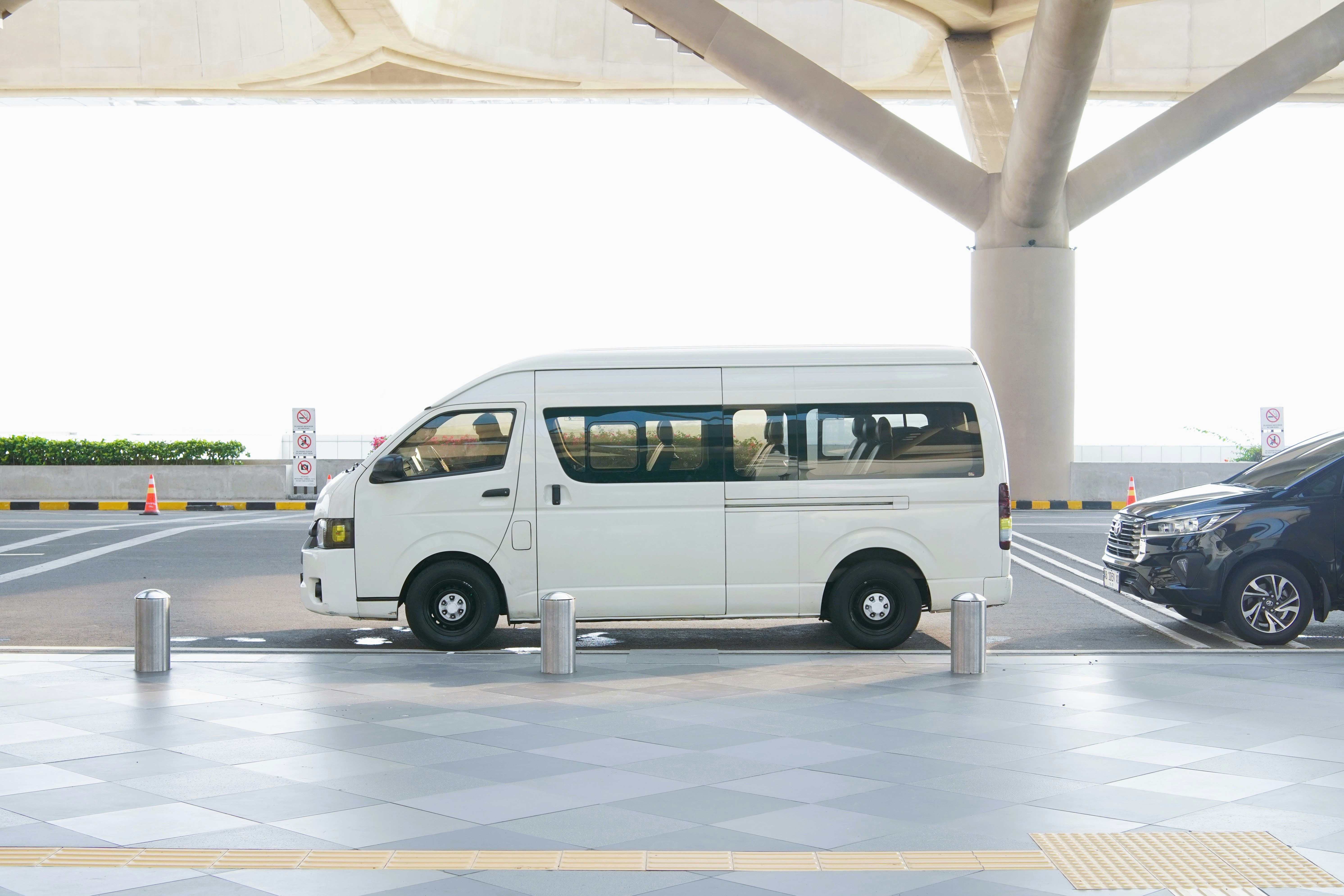 White minivan under architectural canopy in sunlit outdoor lot