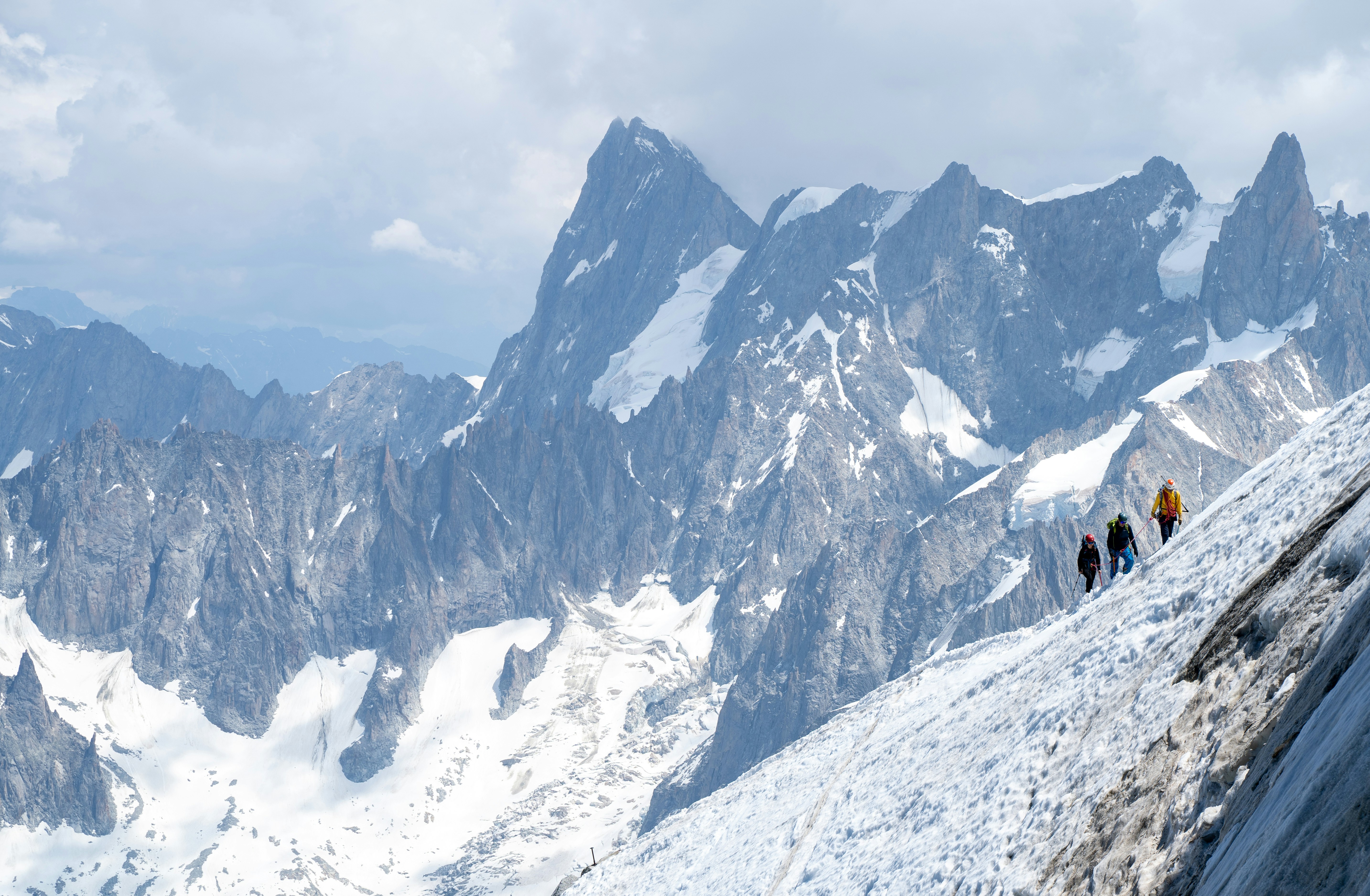 Climbers Ascend a Snow-White Ridge Under Jagged Peaks