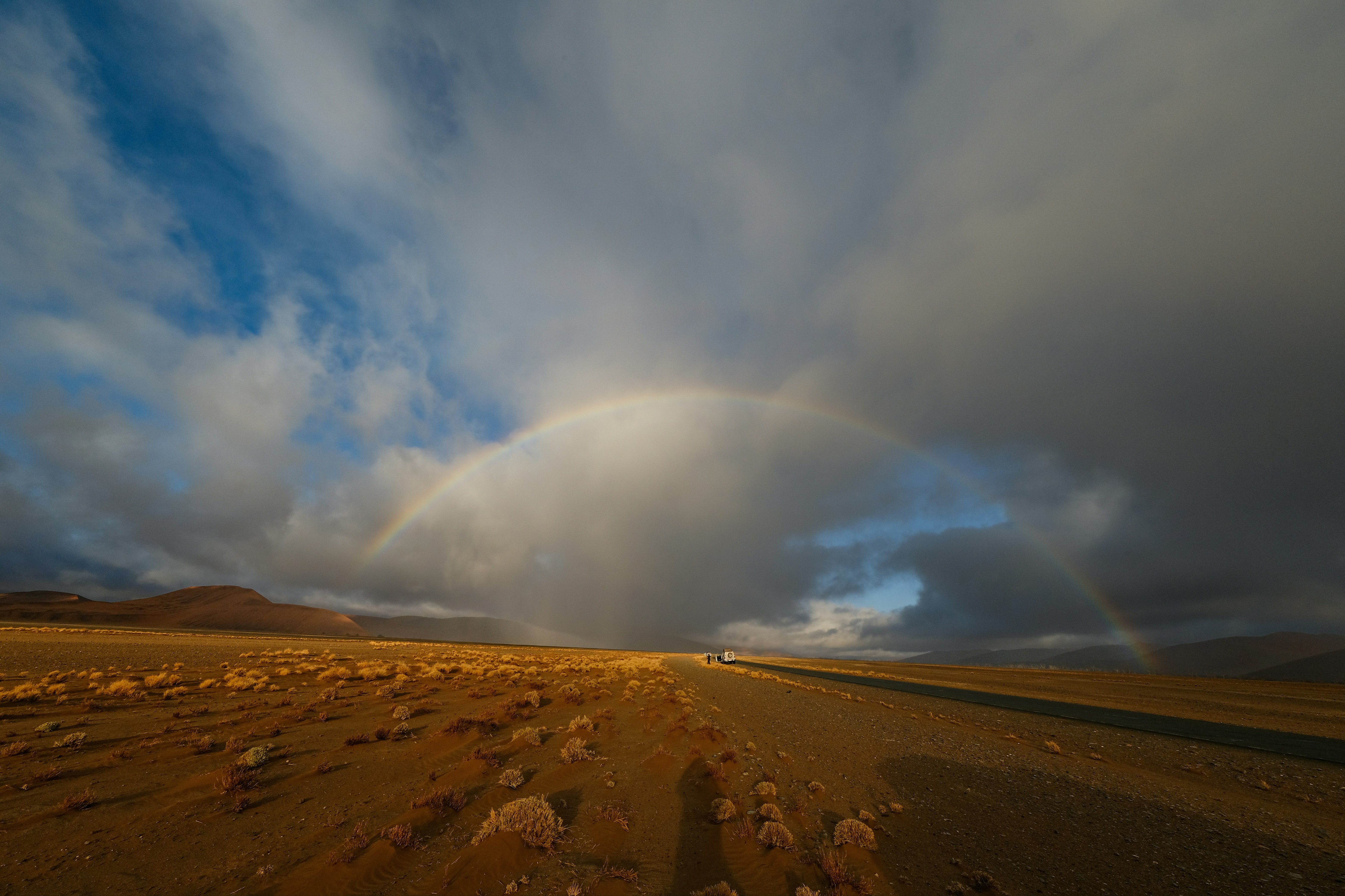 Rainbow Crown Over Dusty Road: A Quiet Arc in the Desert Light