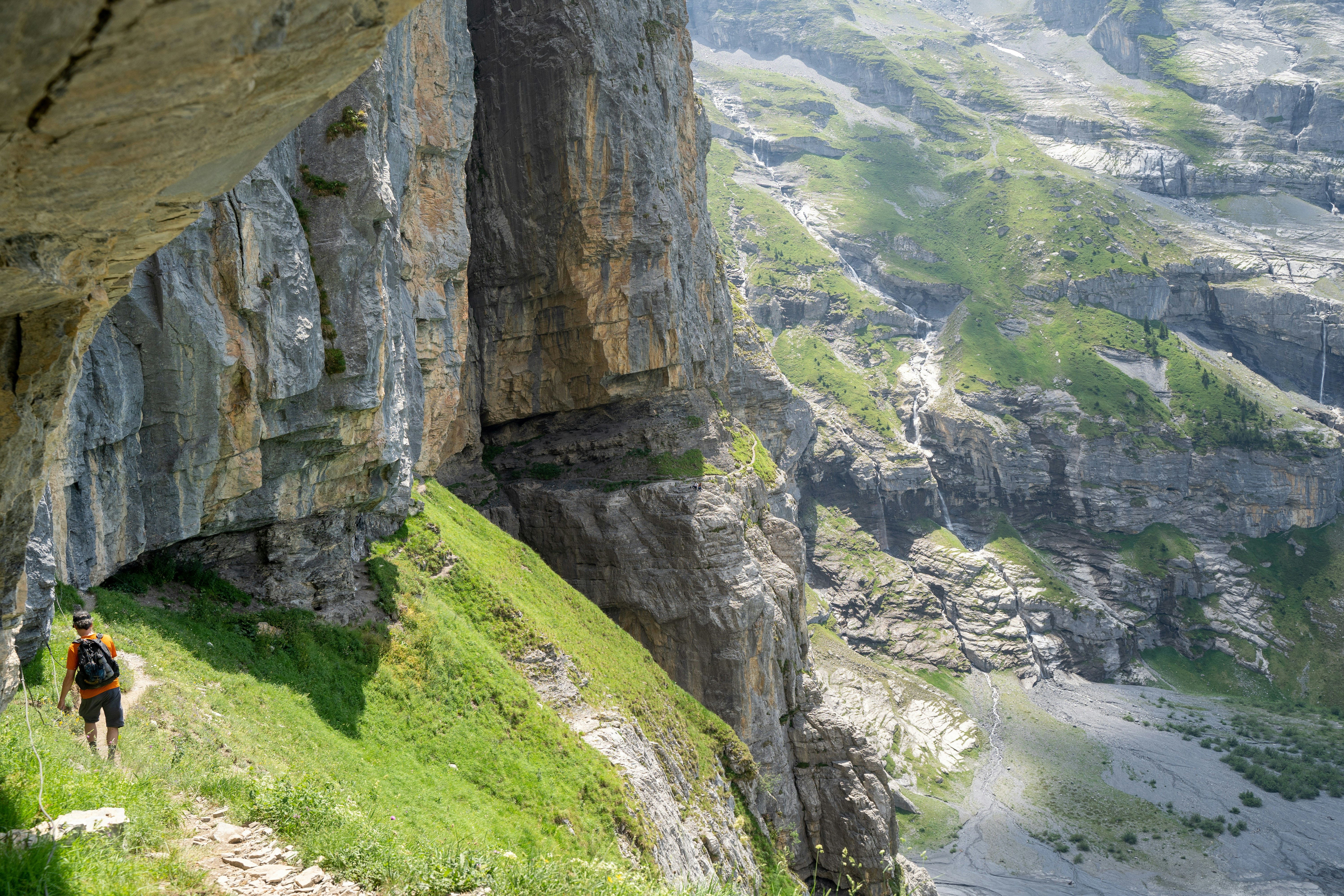 Climber on a Narrow Alpine Ridge Beneath a Vertical Cliff