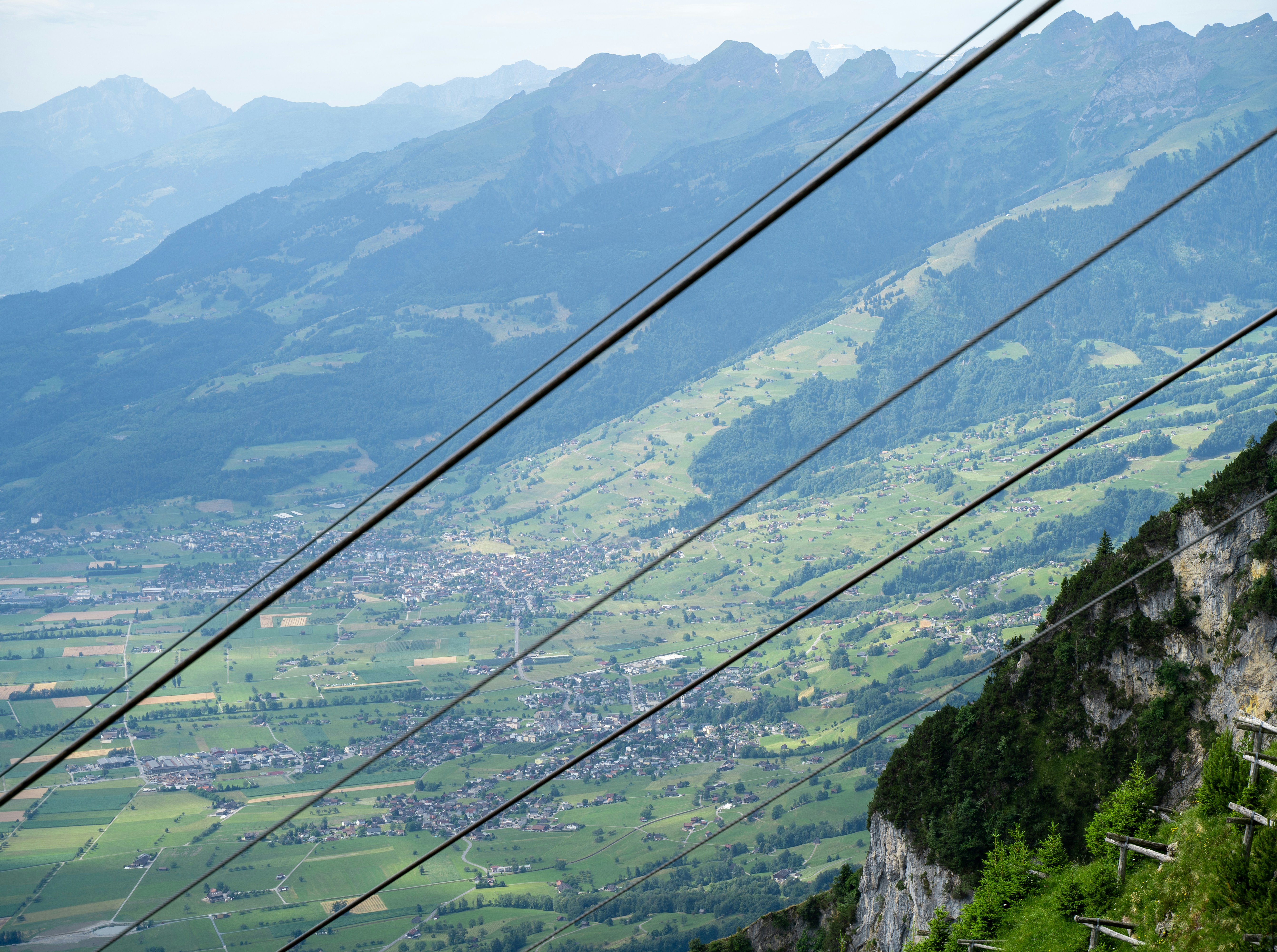 Cable Lines Traversing a Verdant Valley Between Alpine Slopes