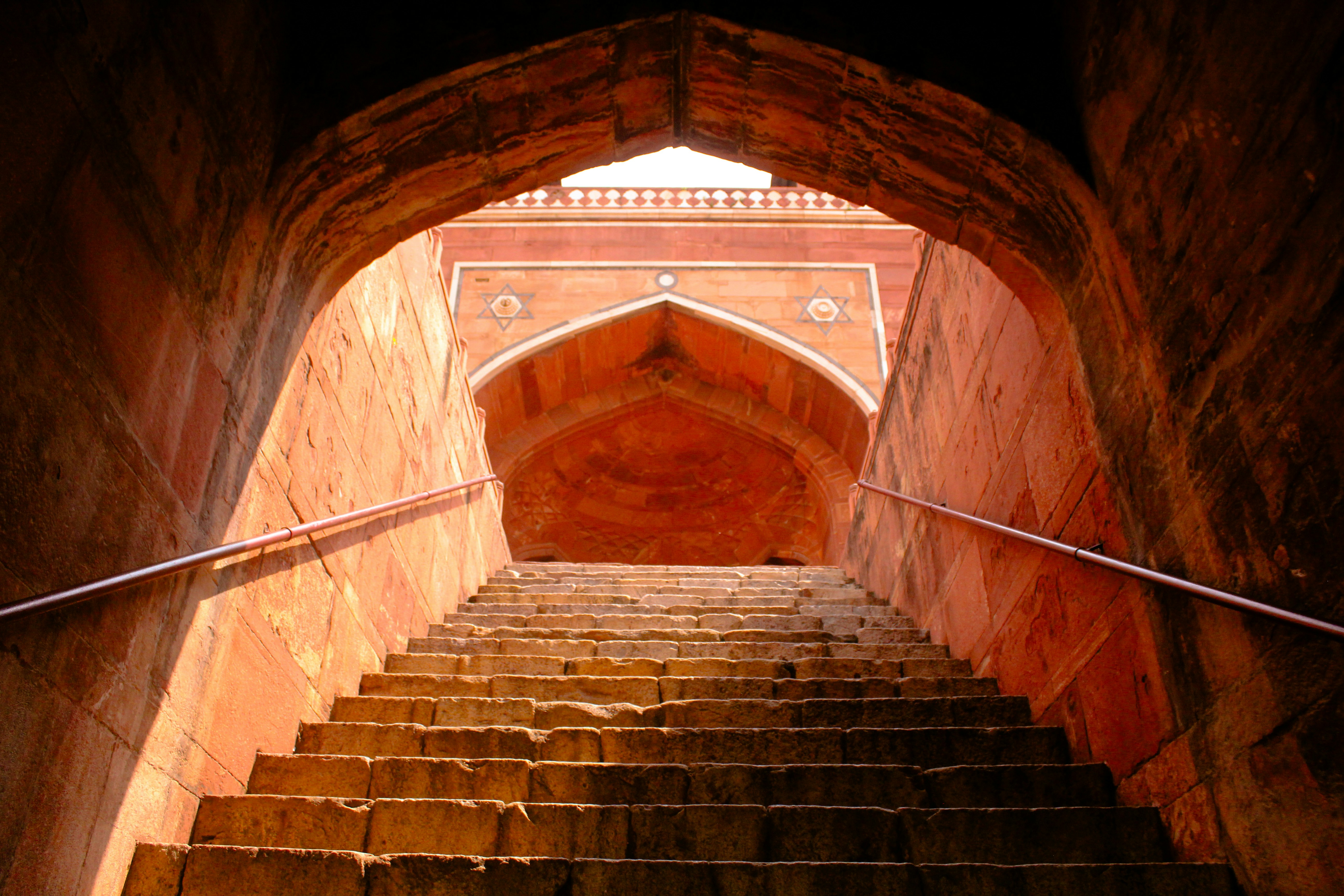 Sunlit Archway: A Descent into Warm Red Stone