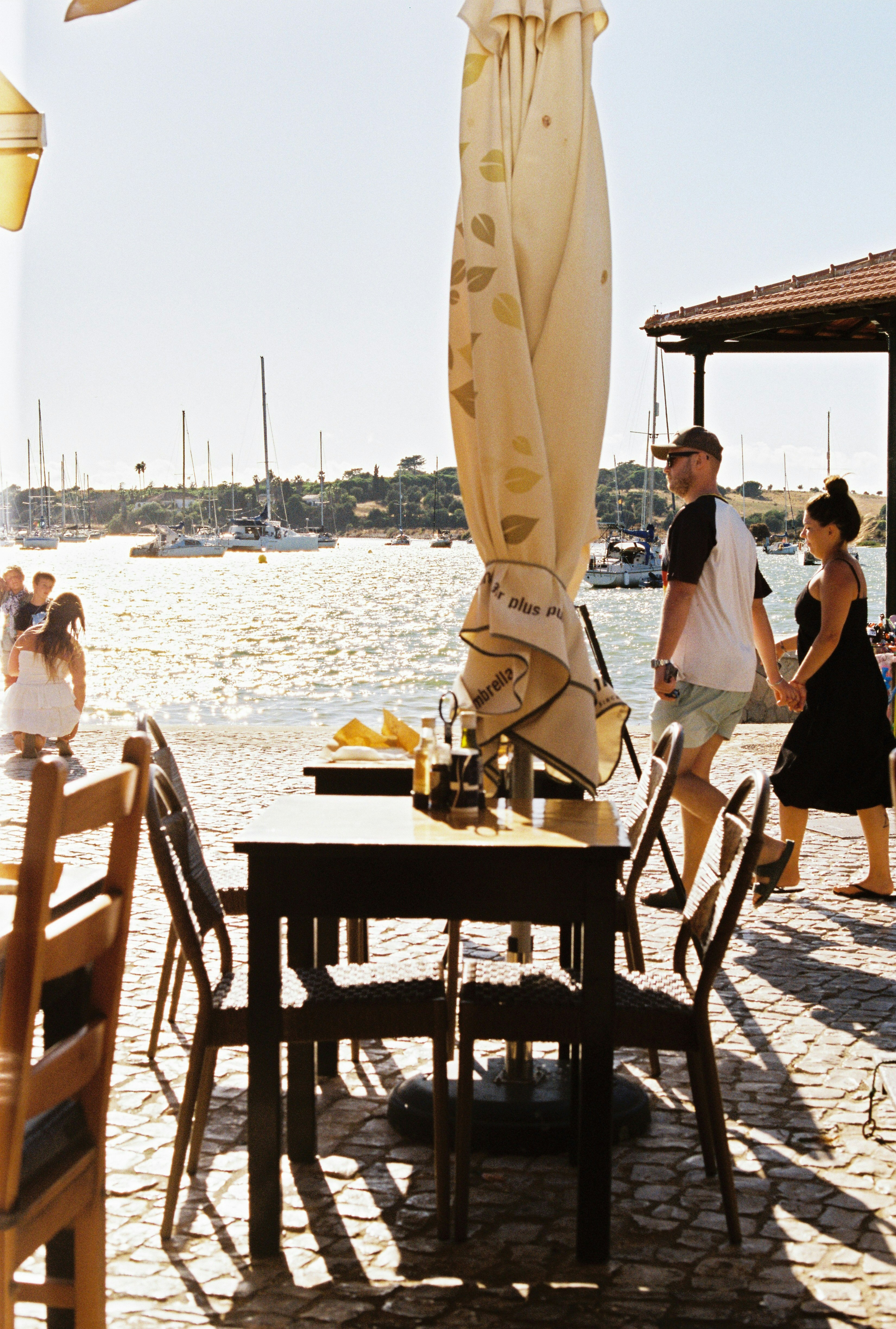 Sunlit Terrace by the Harbor: Quiet Table Beneath a Folded Umbrella