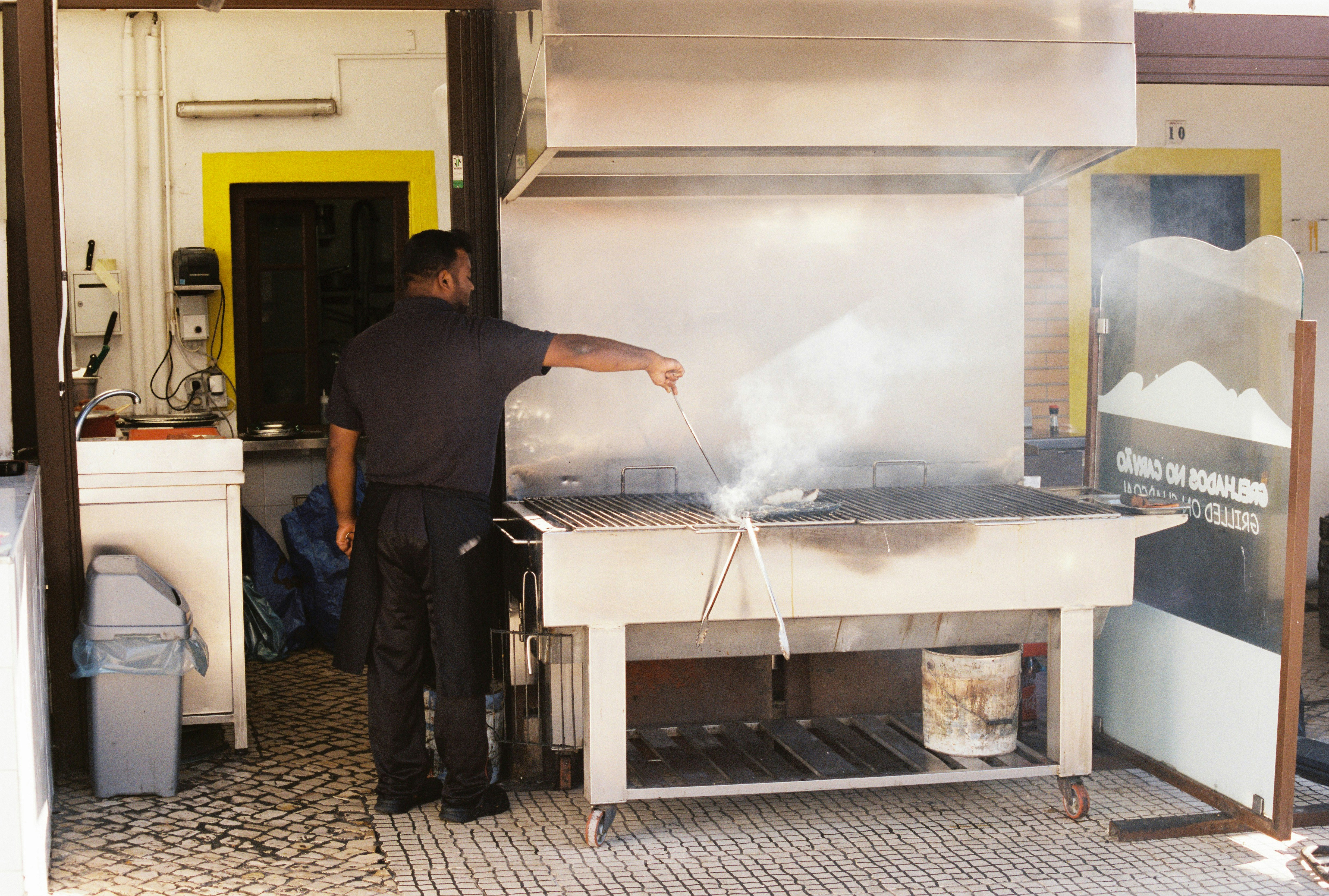 Grillmaster at Work: Steam and Smoke in a Quiet Urban Kitchen