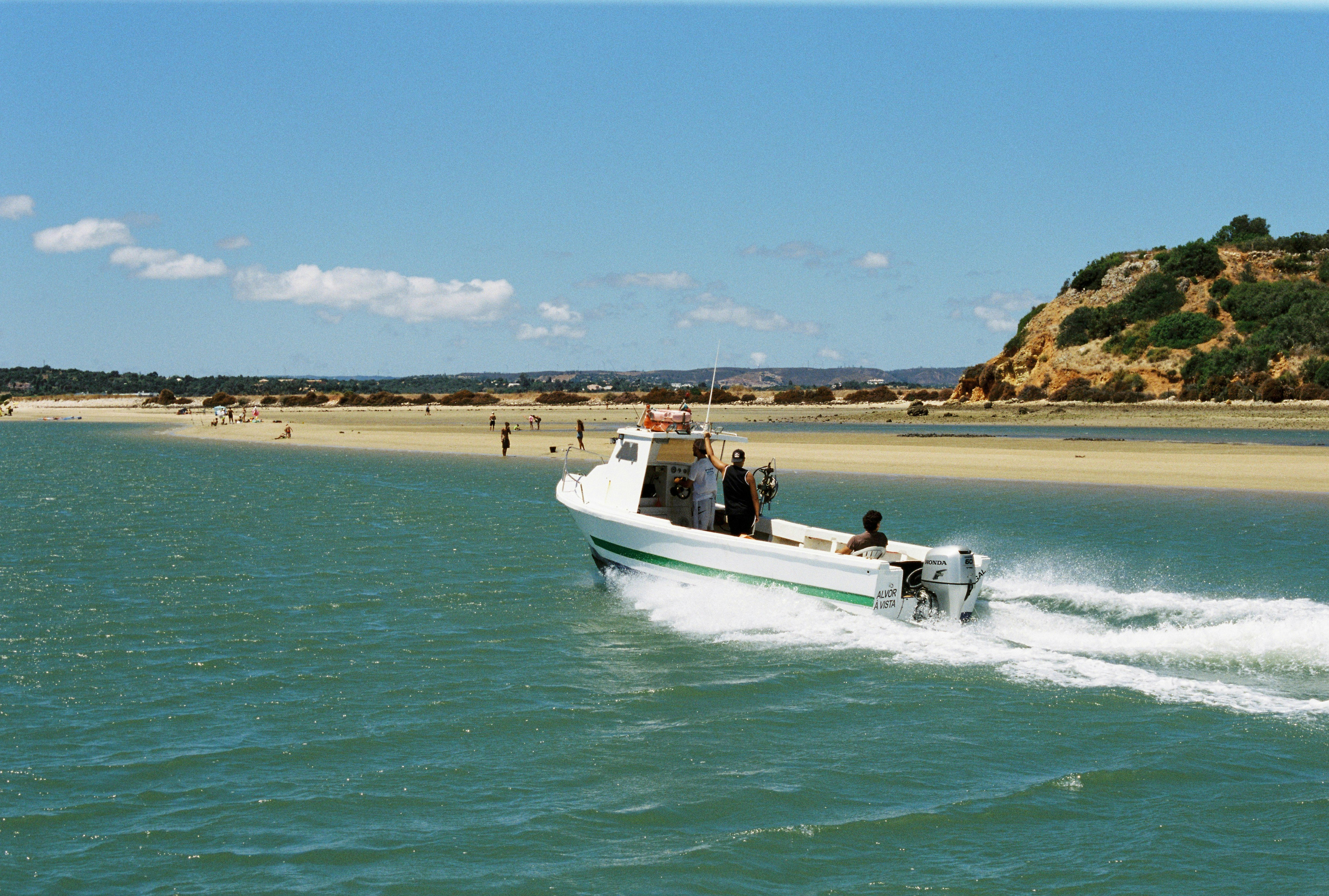 White speedboat slicing through turquoise waters along a sunlit shoreline