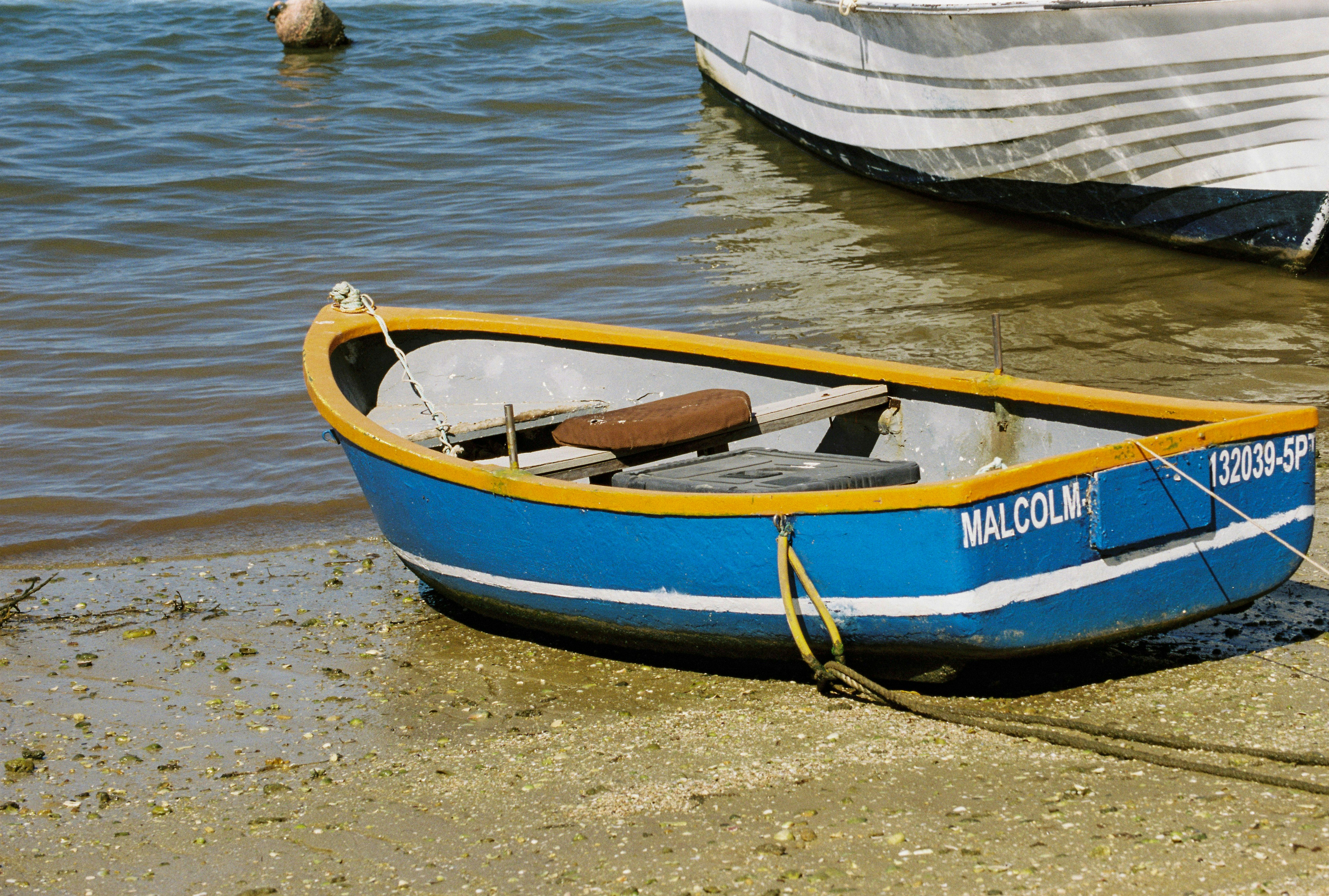 Blue Rowboat on Tidal Shore with Railing of a Larger Vessel