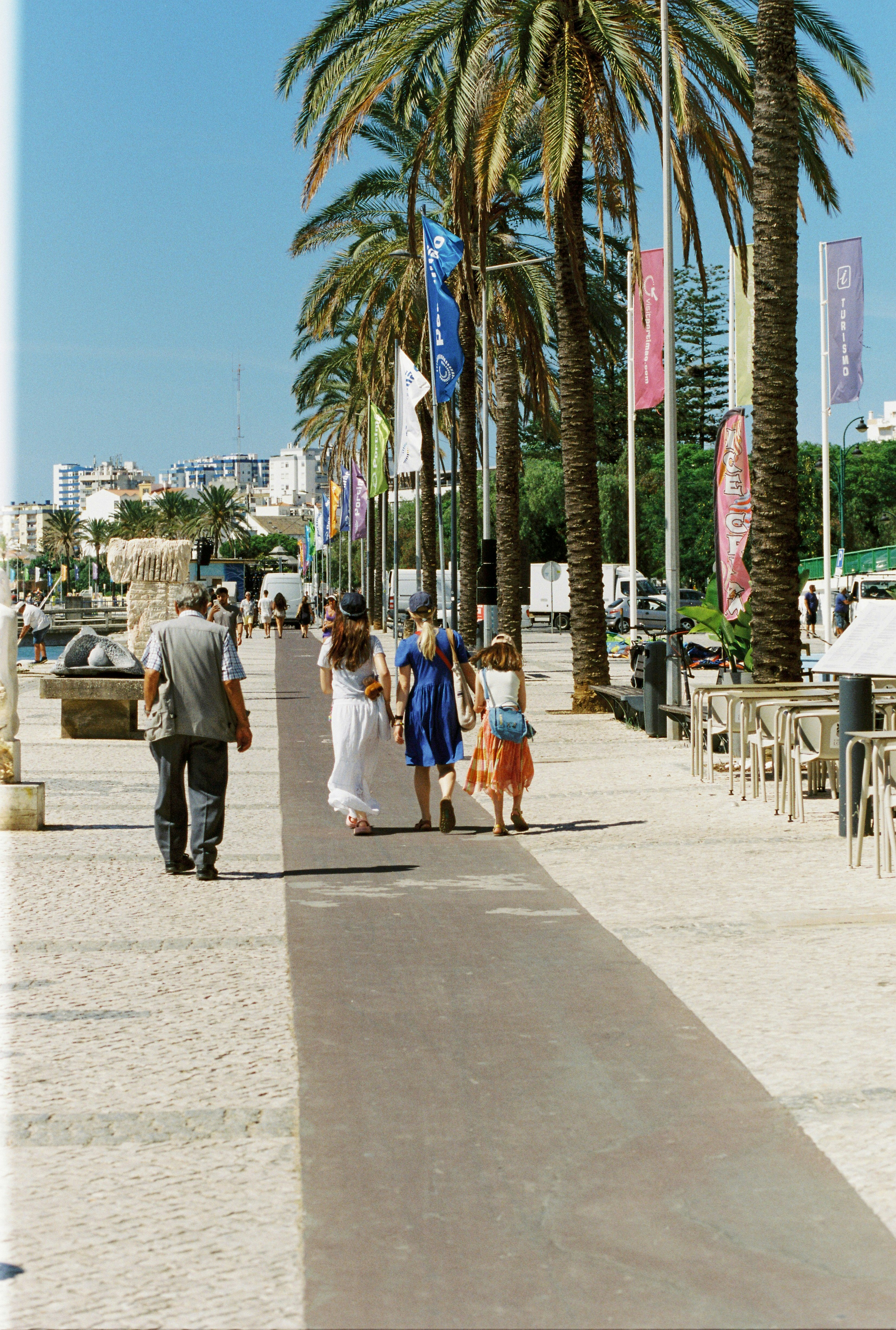 Sunlit promenade: a family stroll beneath palm-lined banners