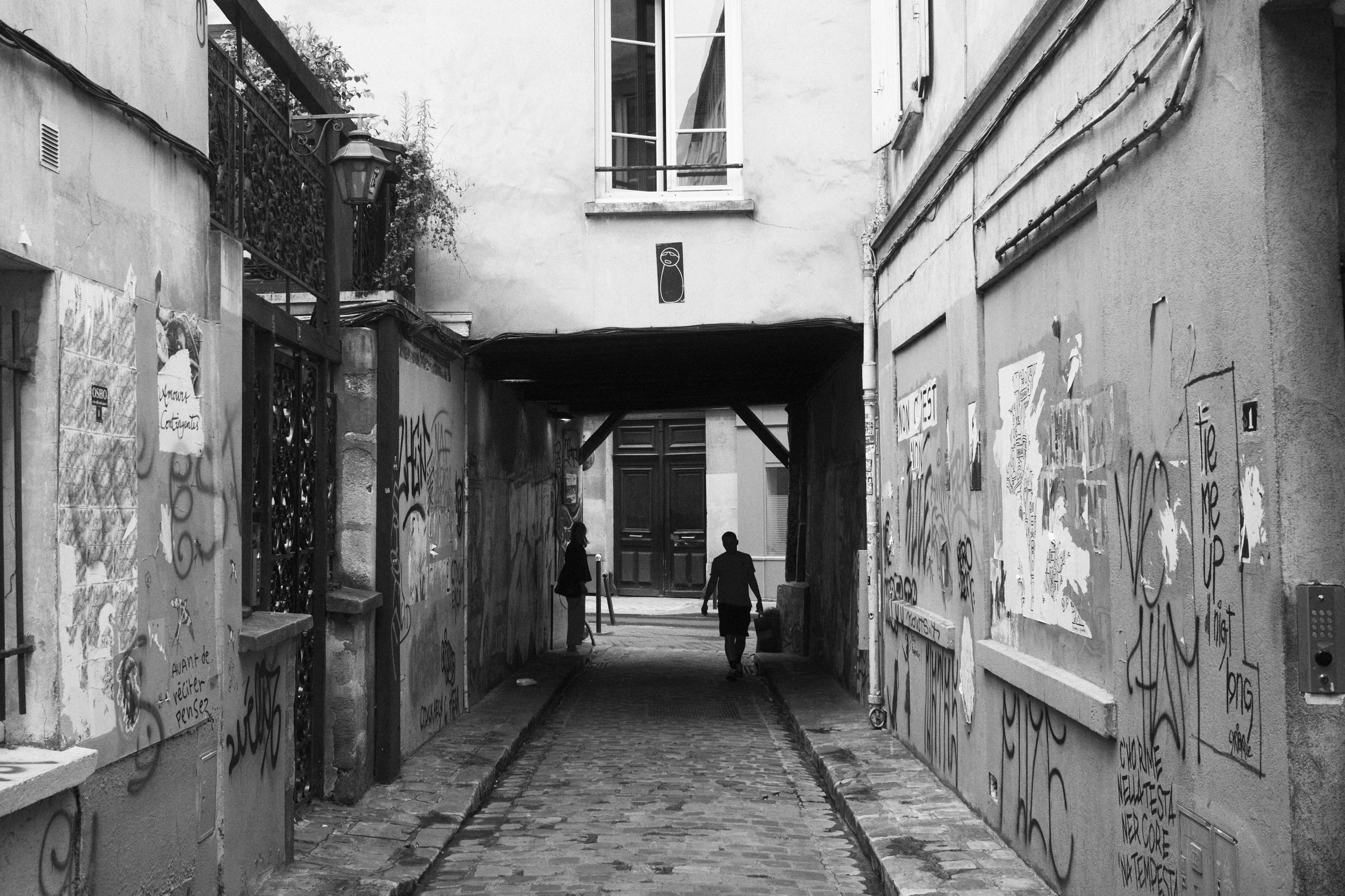 Urban Passage: Graffiti-Walled Alley Leading to a Sunlit Archway