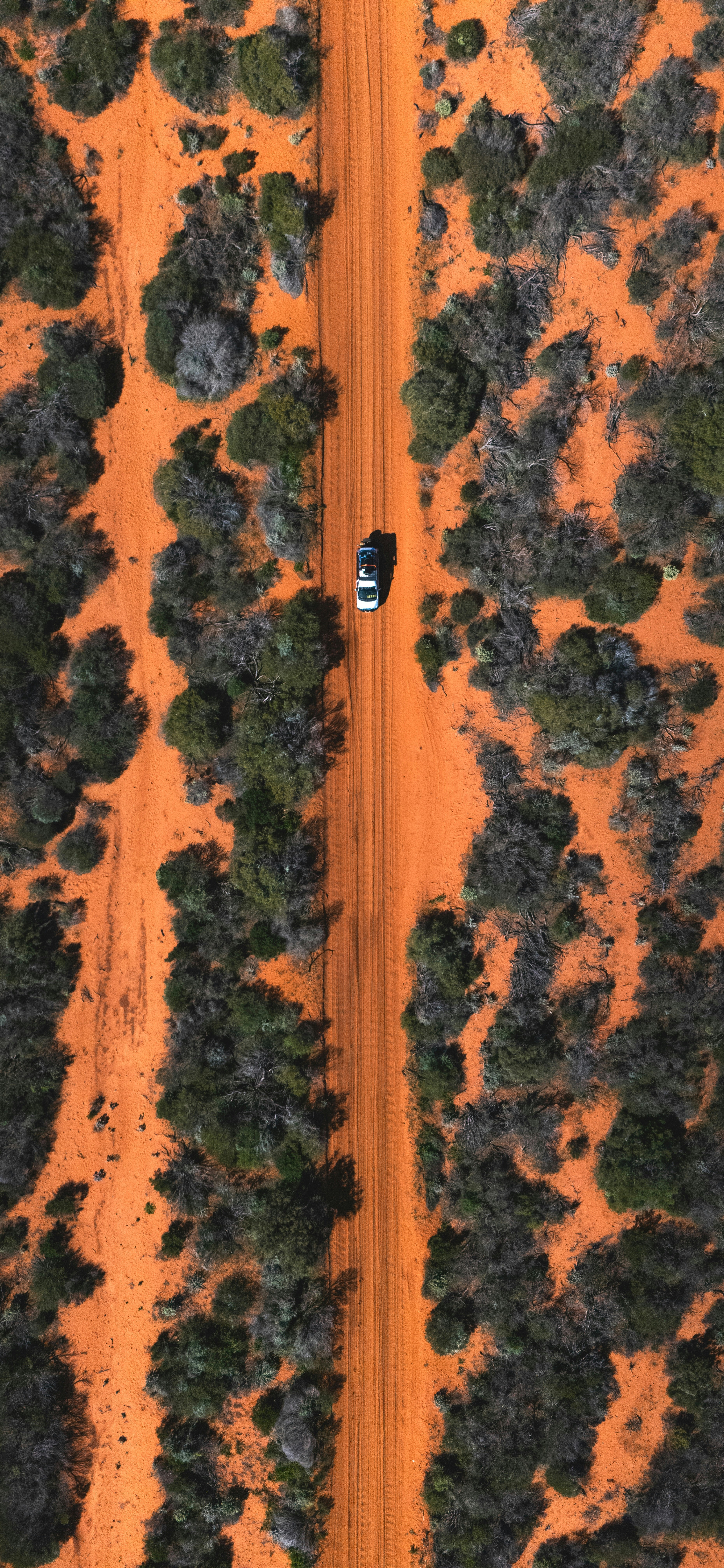 Crimson Highway: A Lone Vehicle Traverses a Desert-Rust Horizon